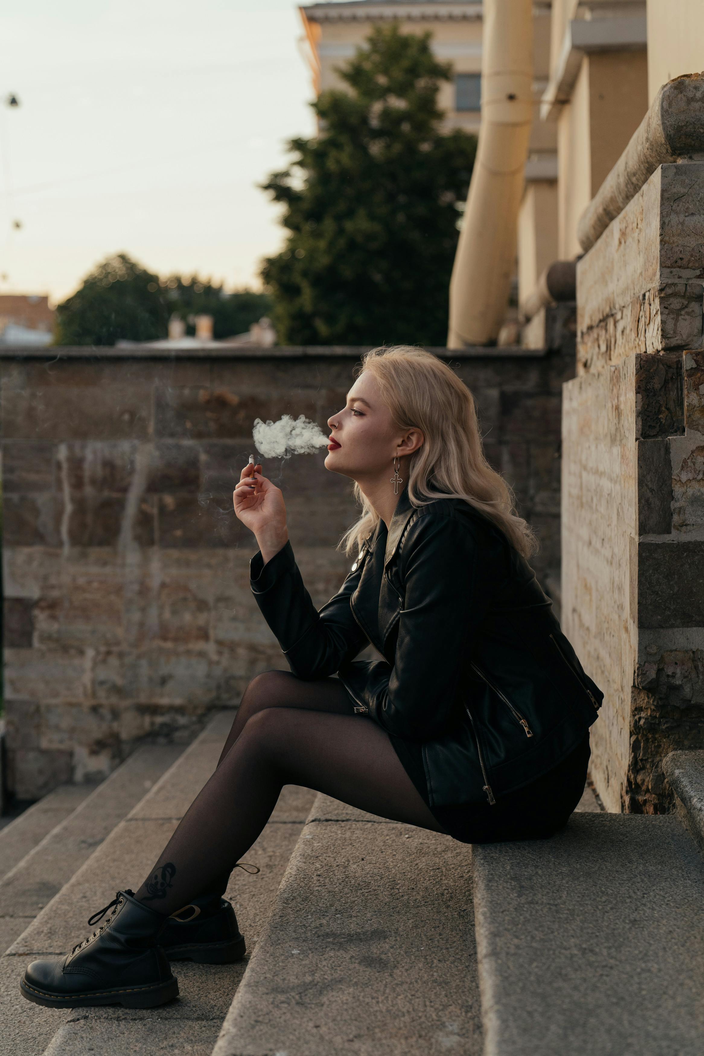 A Young Woman Smoking while Sitting on the Stairs · Free Stock Photo