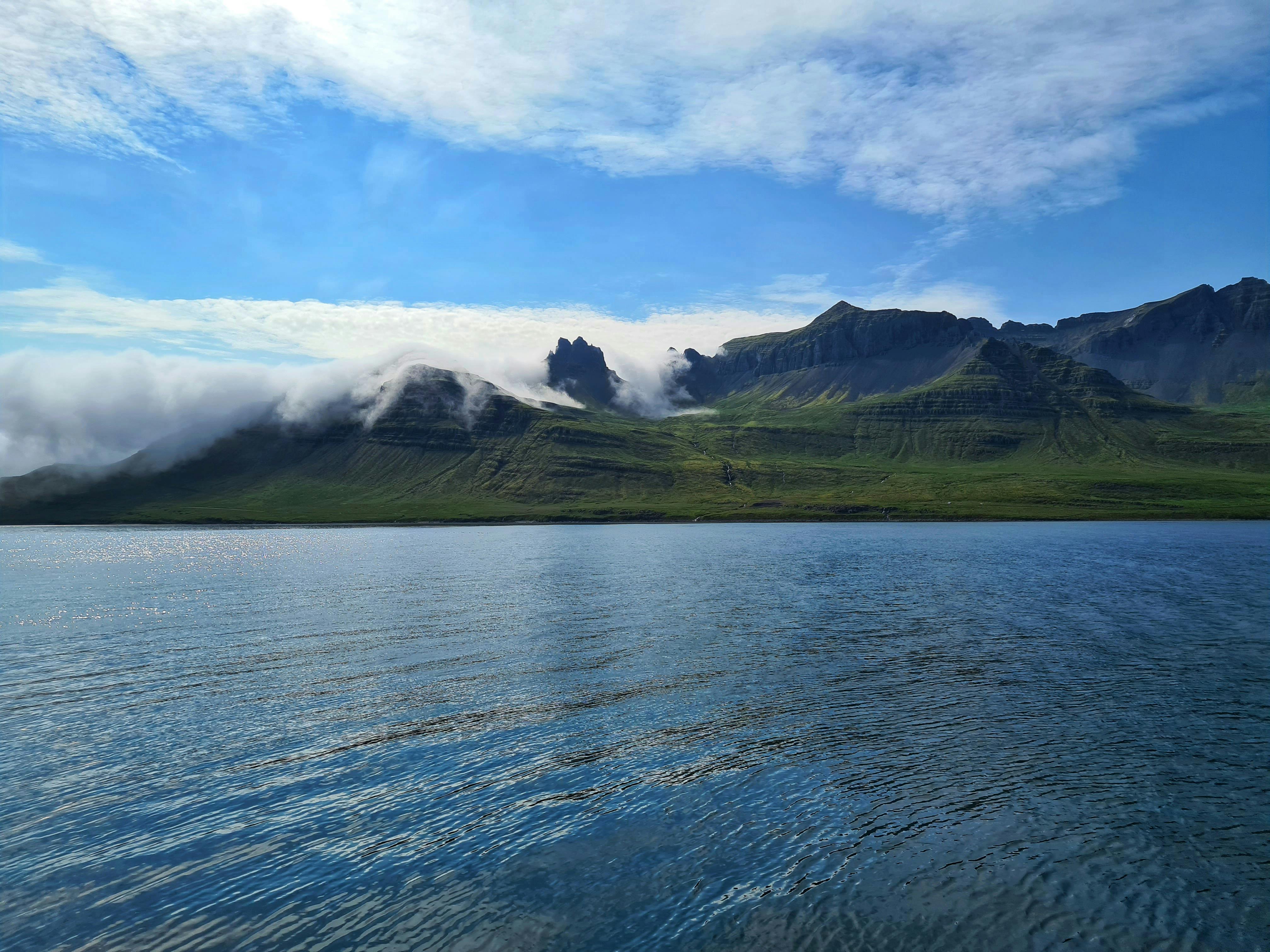 Rippling water surface near high mountains in clouds · Free Stock Photo