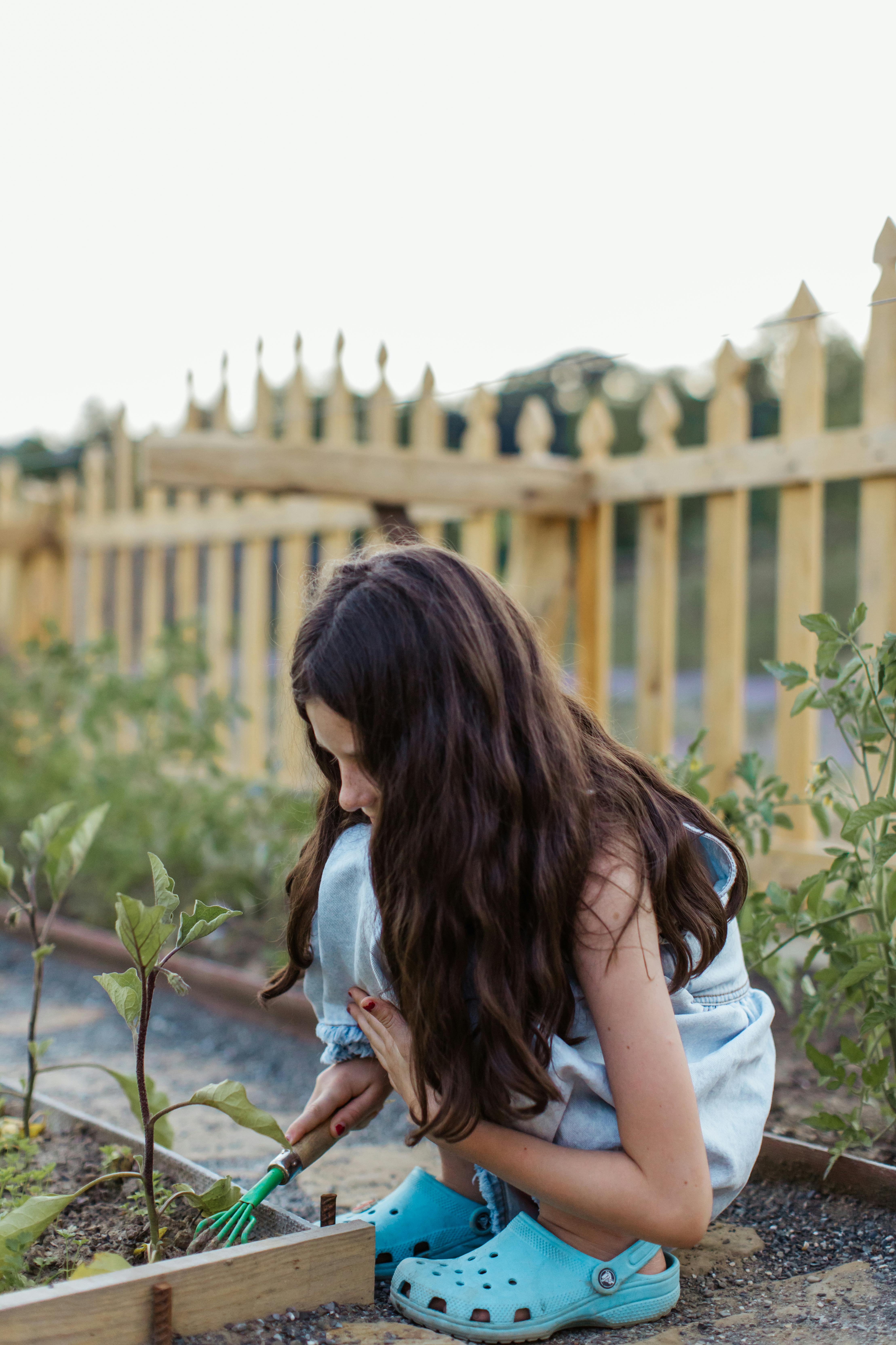 Young Girl Planting Using Gardening Fork · Free Stock Photo