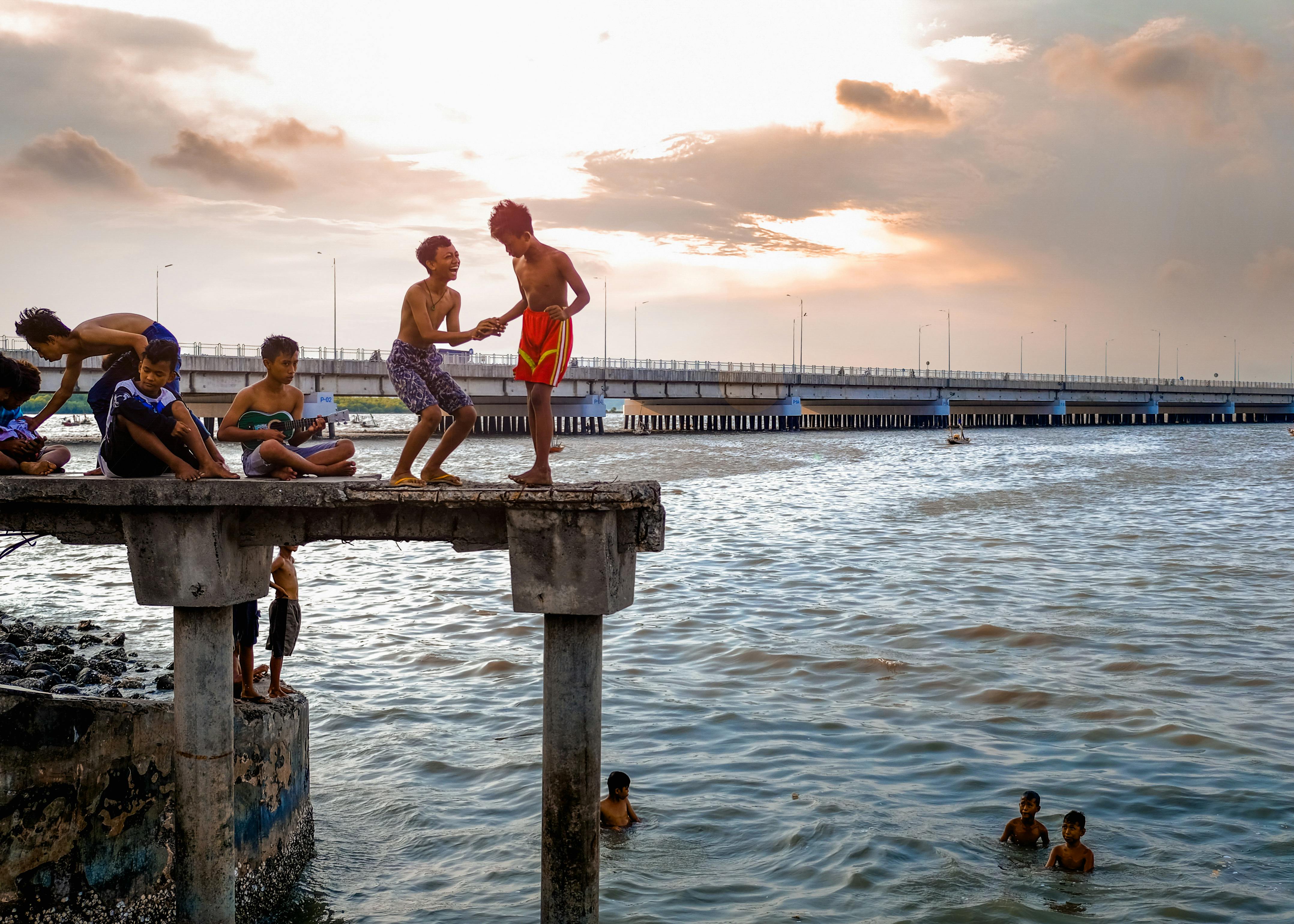 Boys Playing on Jetty by Sea · Free Stock Photo