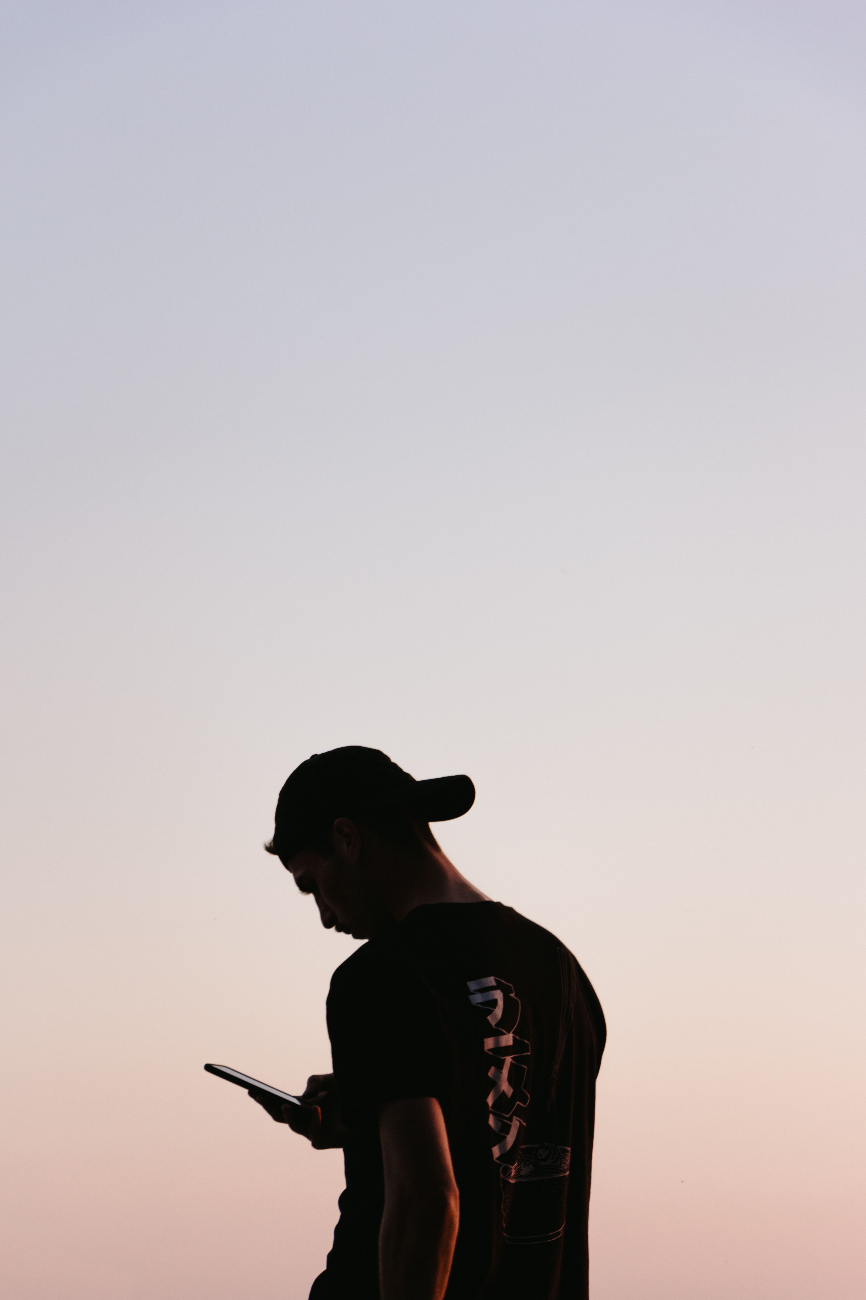 Back View of Man in Cap Standing with Smartphone · Free Stock Photo
