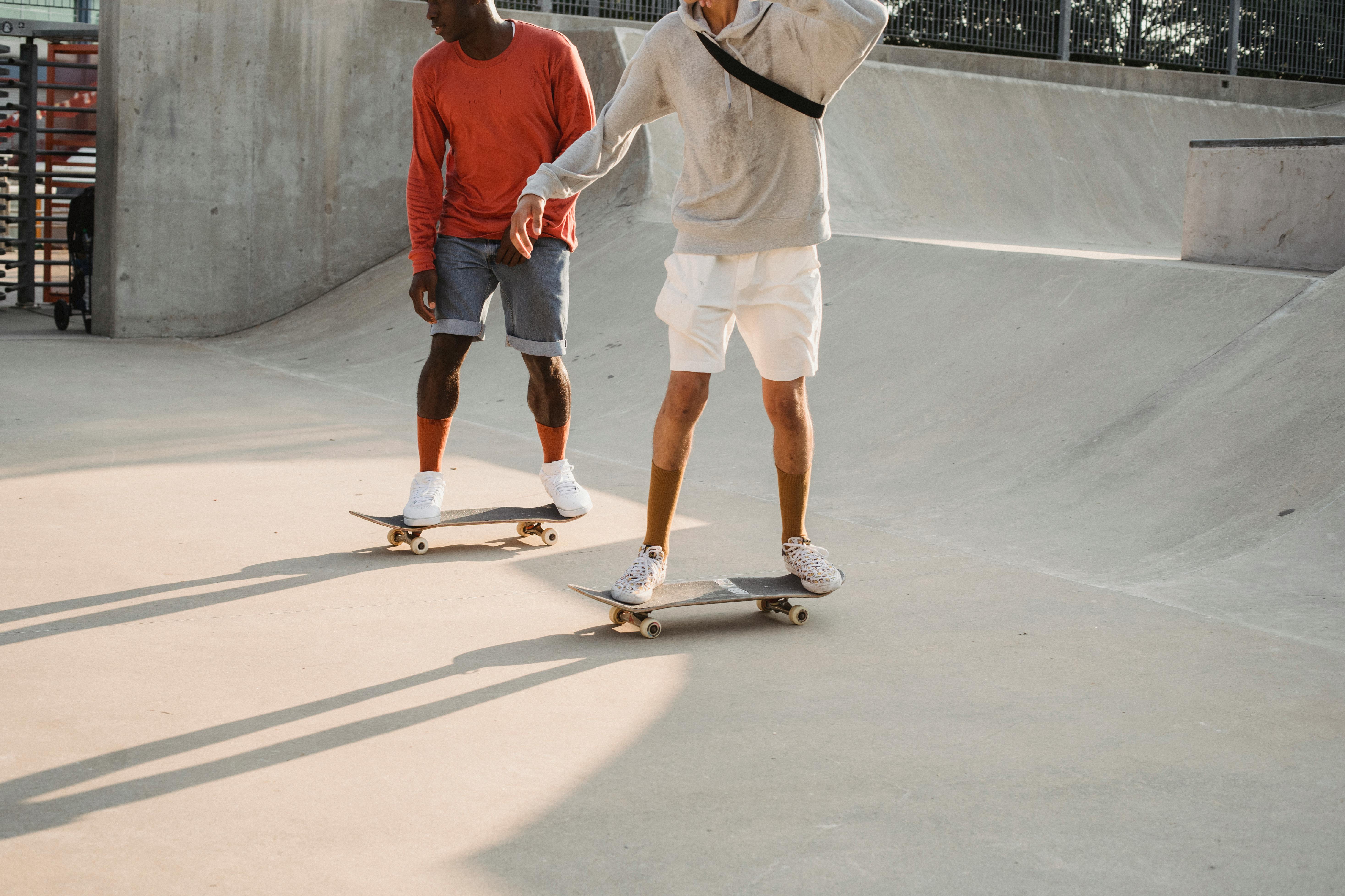 Young friends learning how to ride skateboard on ramp in skate park ...