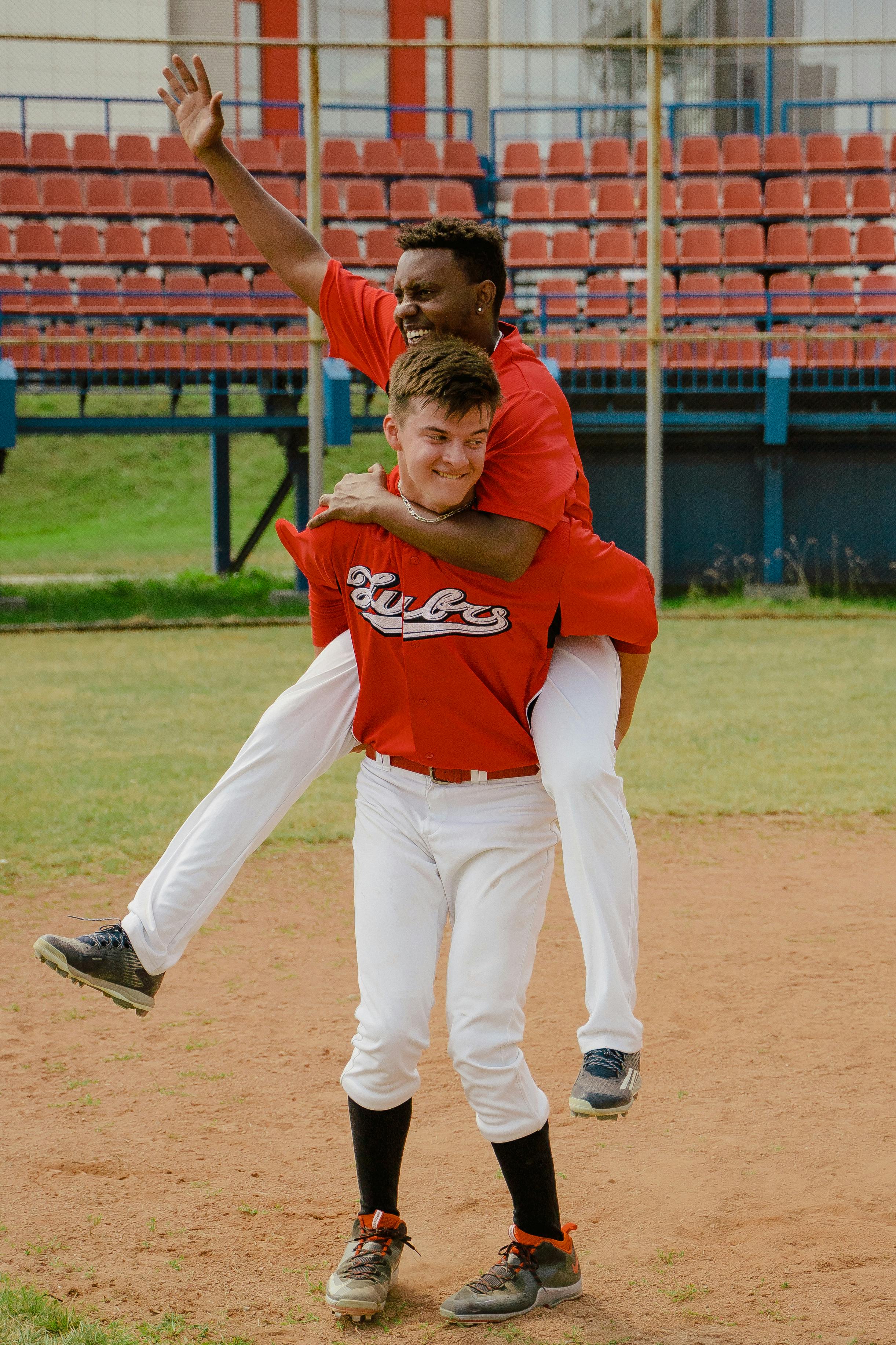 Man in Red Jersey Carrying his Teammate on his Back · Free Stock Photo