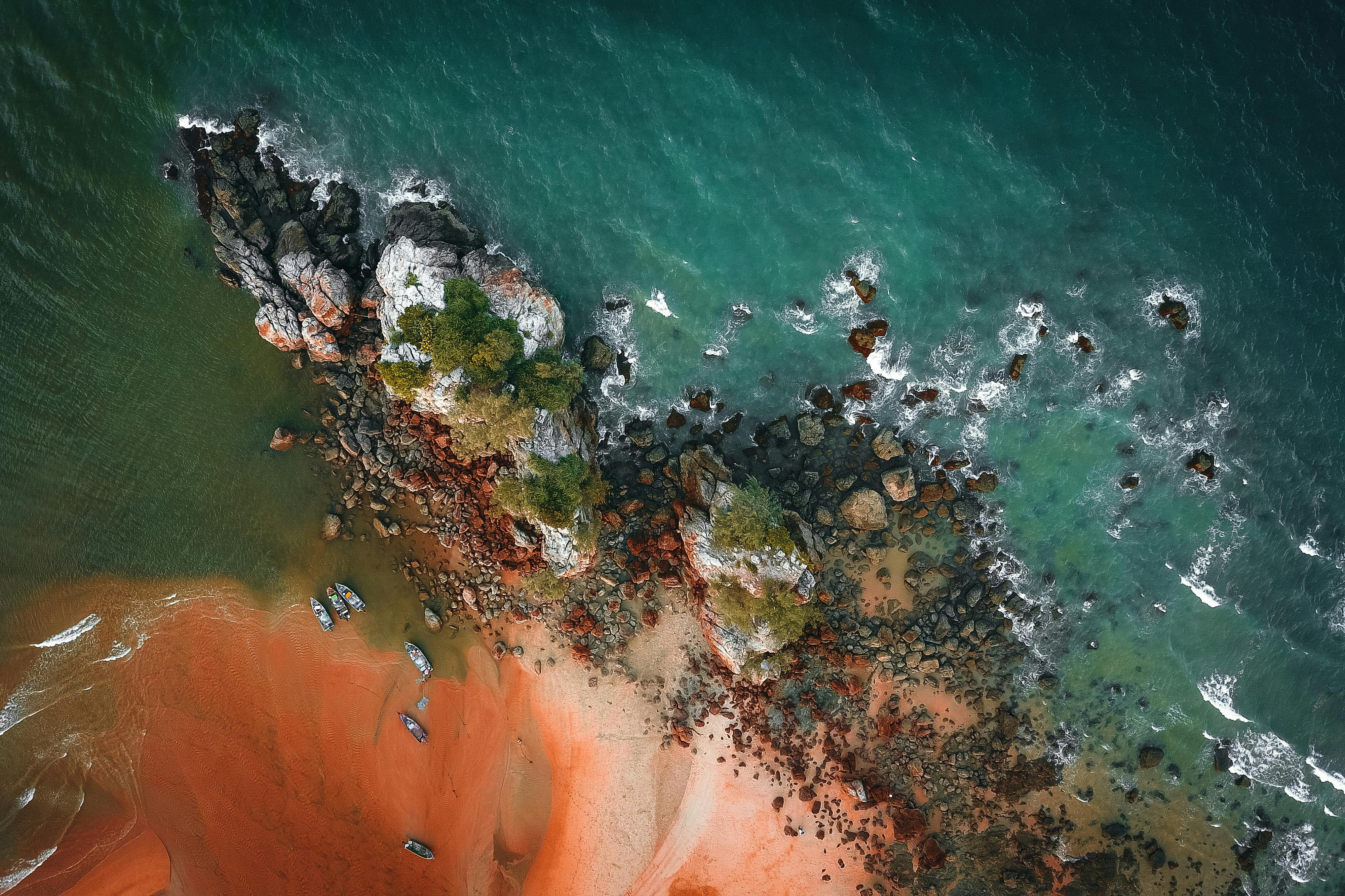 Waving sea washing sandy shore with rocks · Free Stock Photo