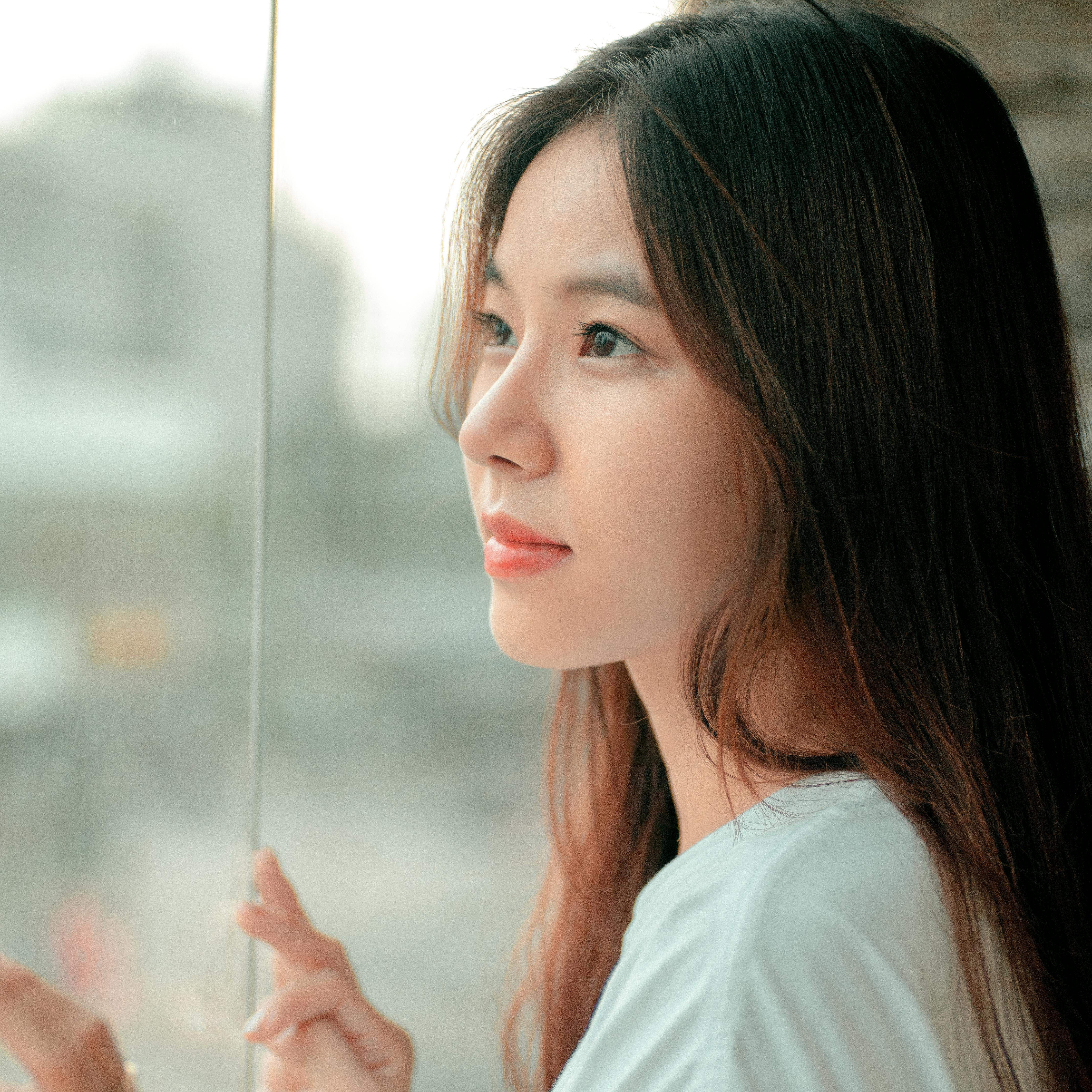 Calm Asian woman standing near glass wall · Free Stock Photo
