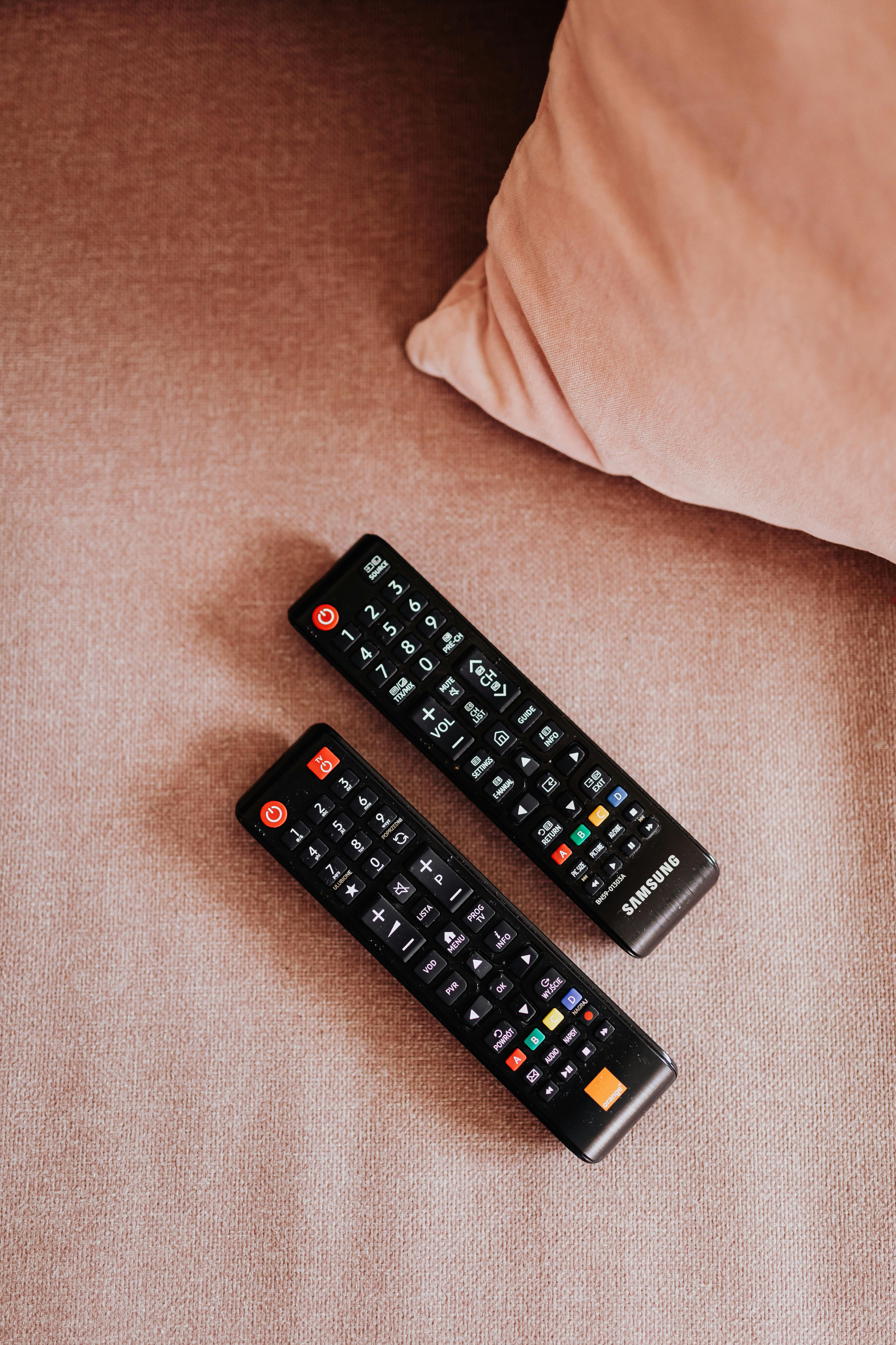 Black Remote Controls on Pink Fabric · Free Stock Photo