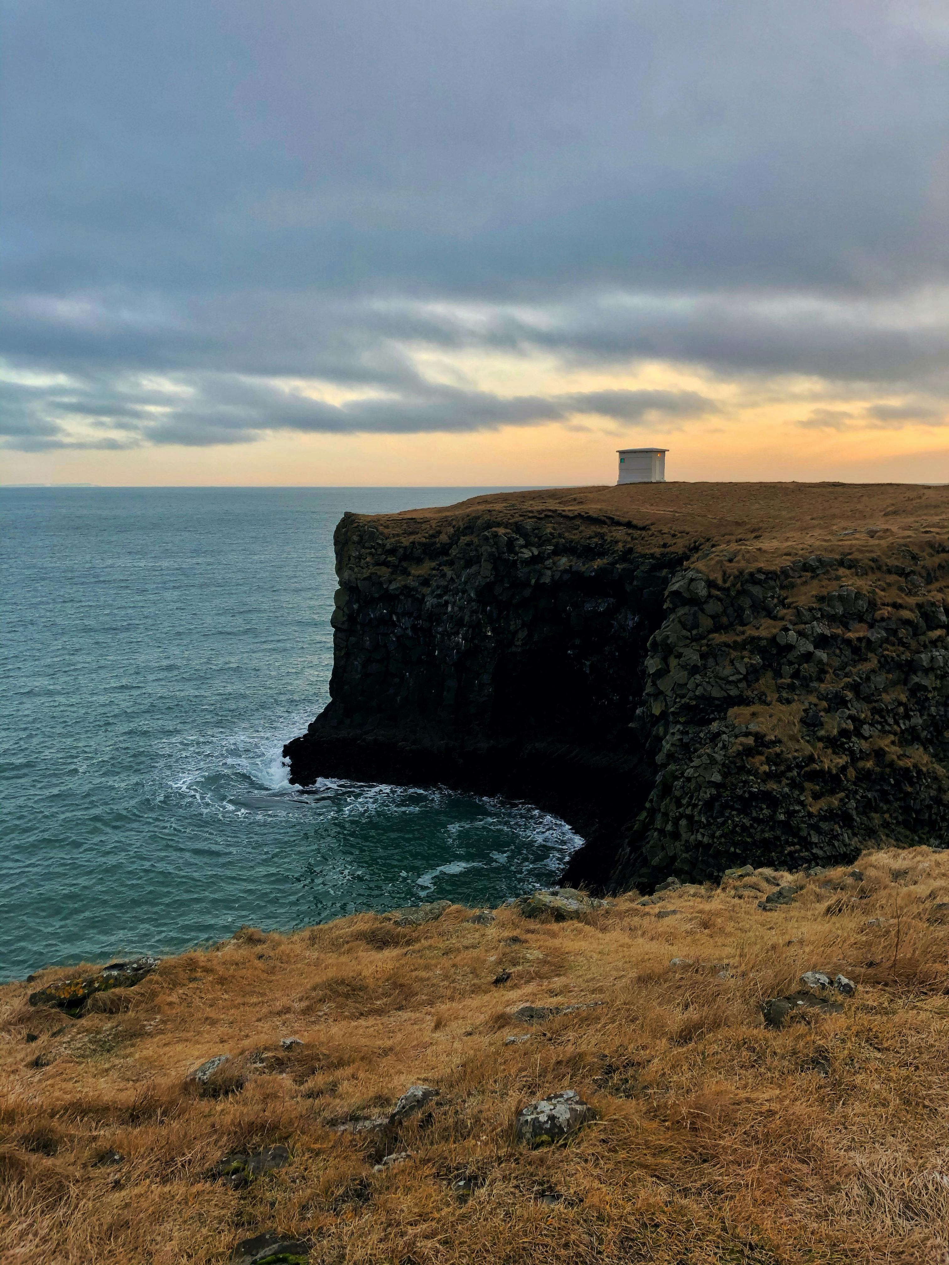 White and Brown House on Cliff Beside Sea · Free Stock Photo