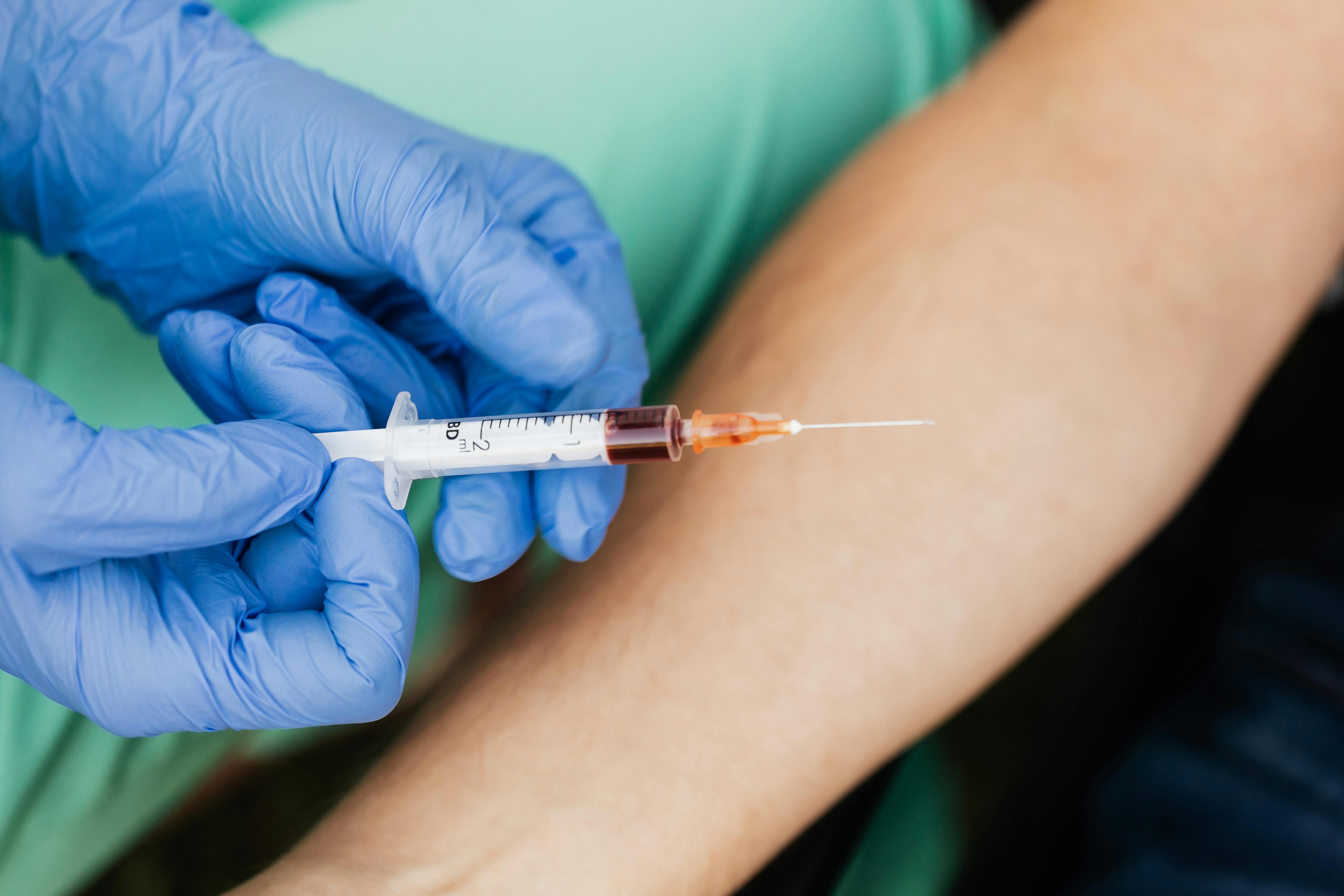 A Close-Up Shot of a Person Holding a Syringe with Blood · Free Stock Photo