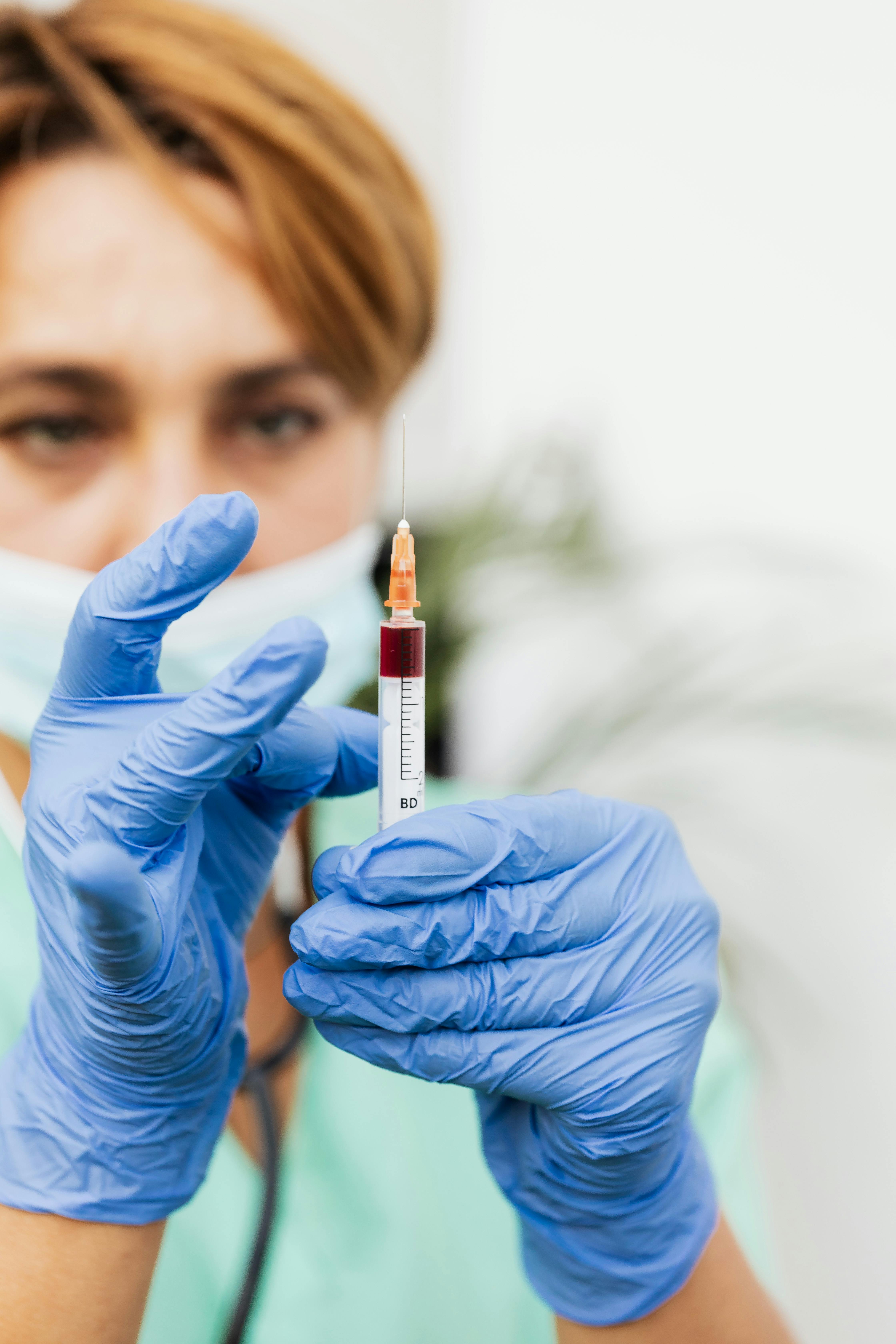 A Doctor Flicking a Syringe with Blood · Free Stock Photo