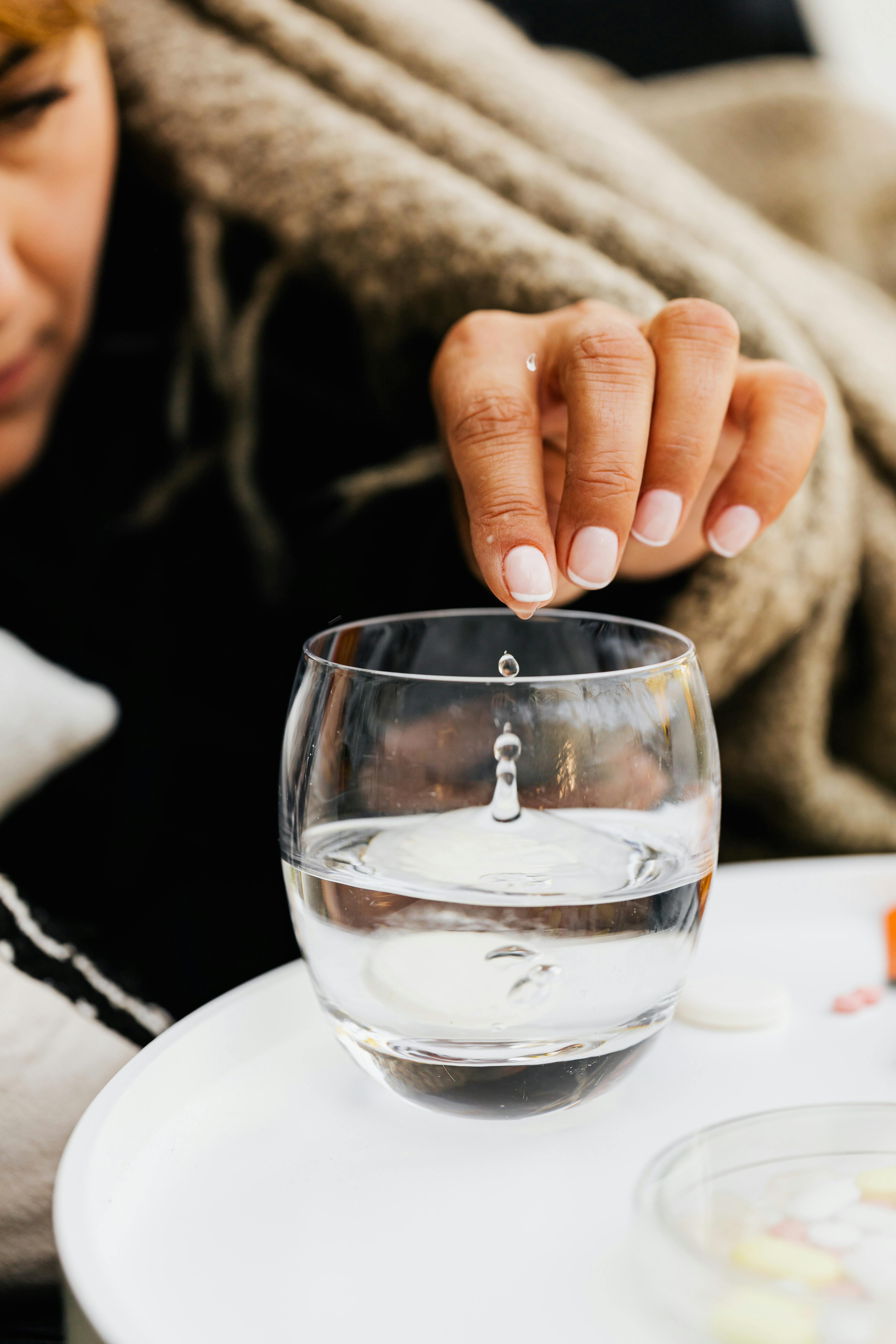 Water Dripping from a Hand into a Glass · Free Stock Photo