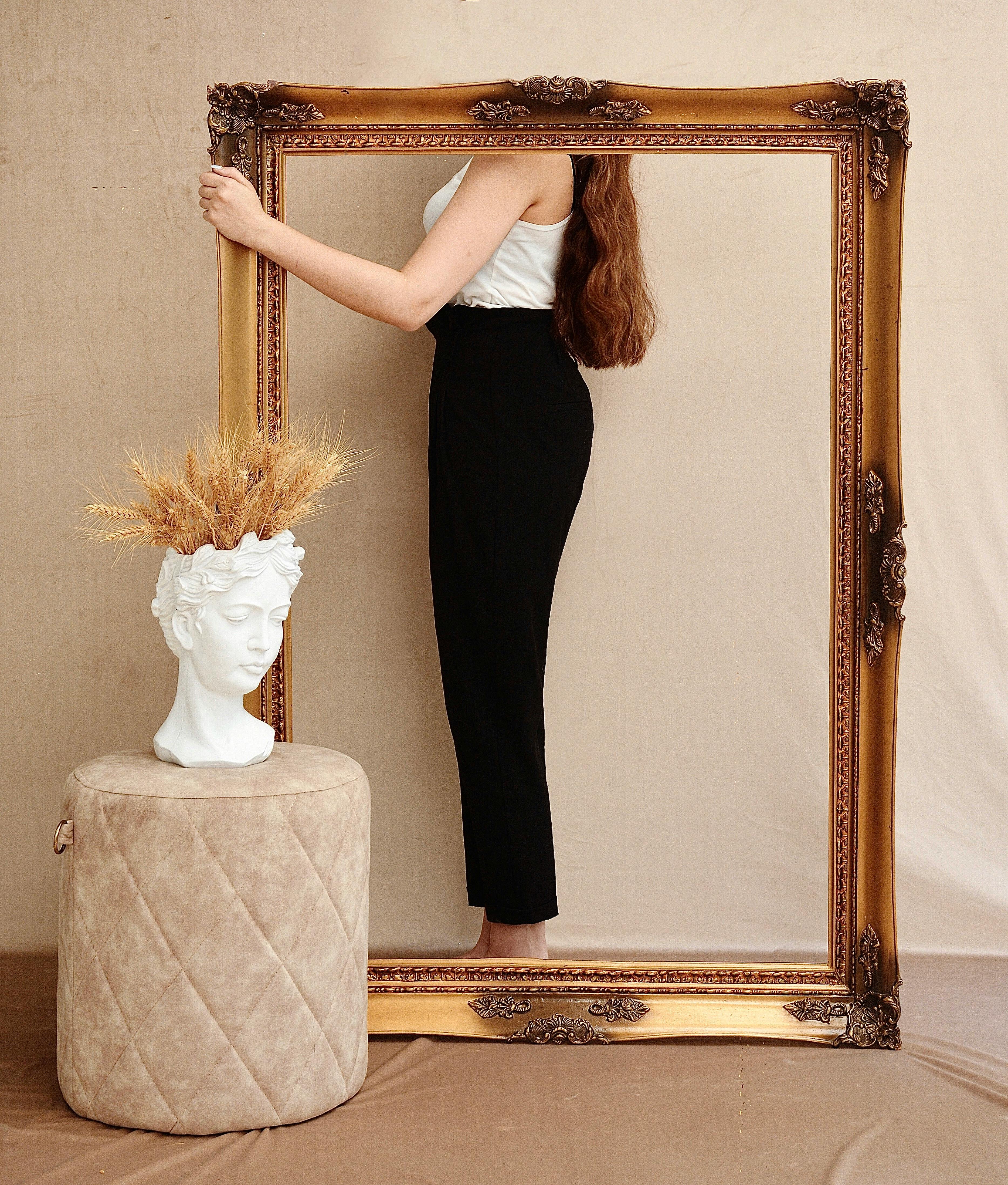 Faceless stylish woman behind ornamental frame in room · Free Stock Photo