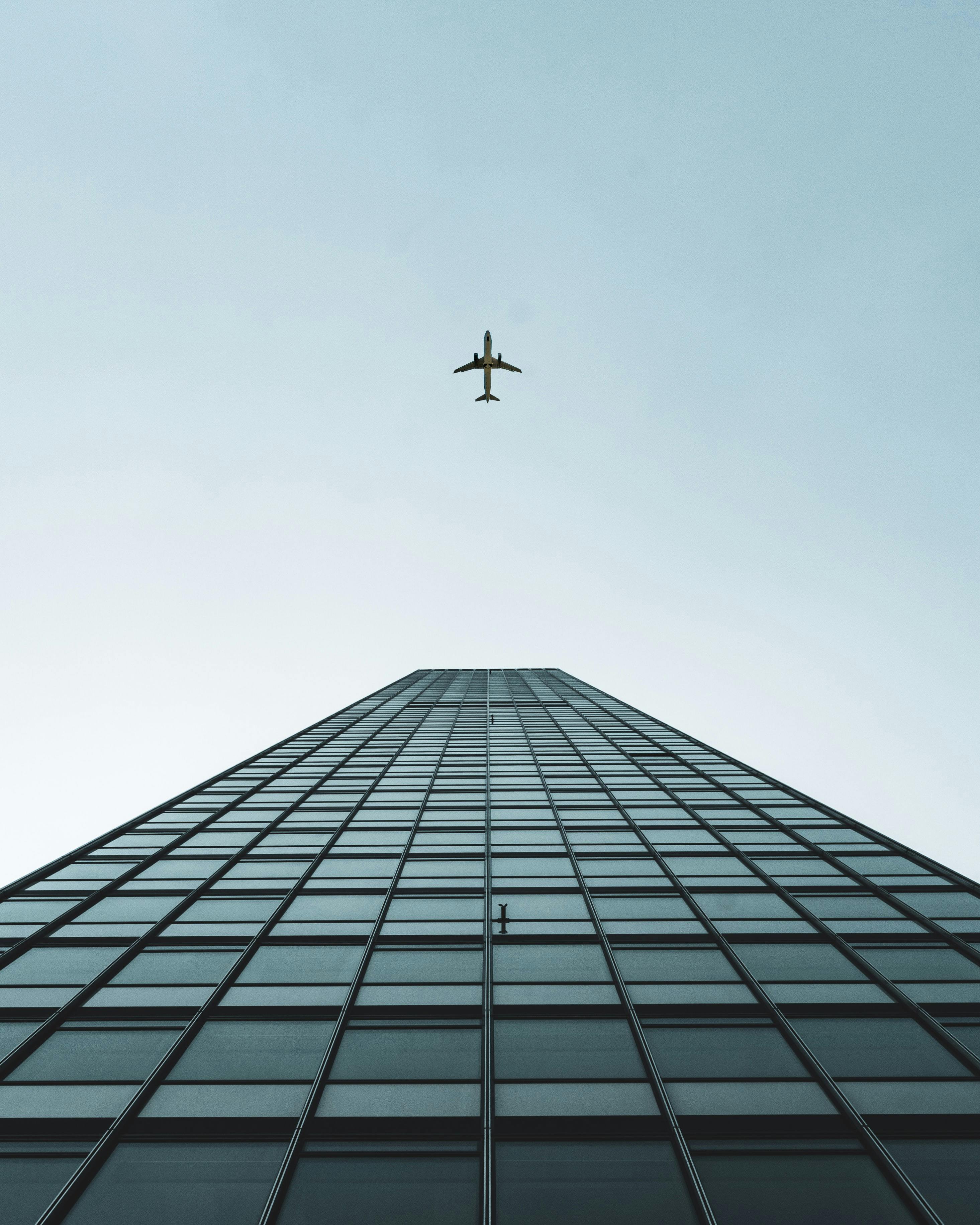 An Airplane Flying Over the Tall Building · Free Stock Photo