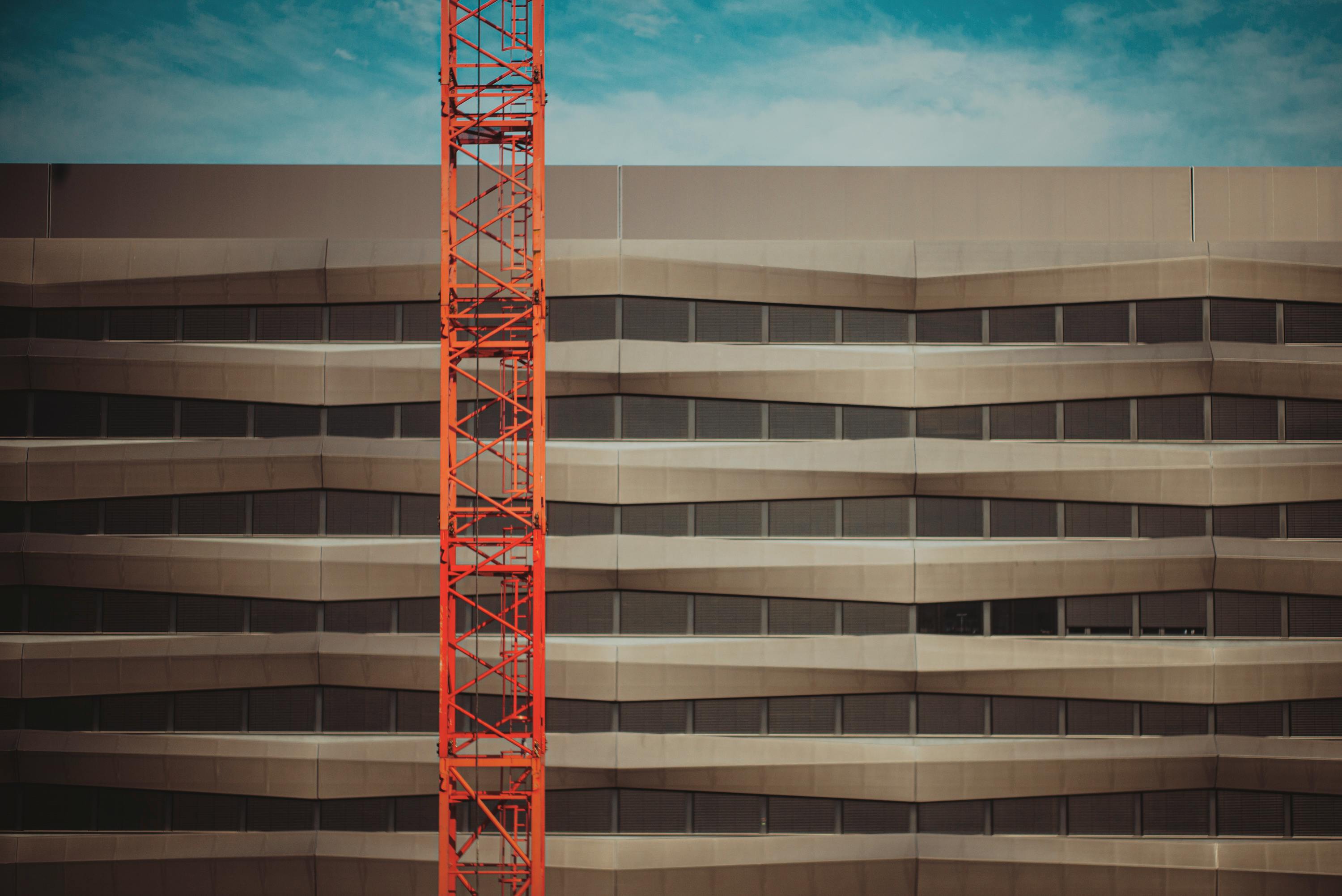 Crane tower against contemporary building in sunlight · Free Stock Photo