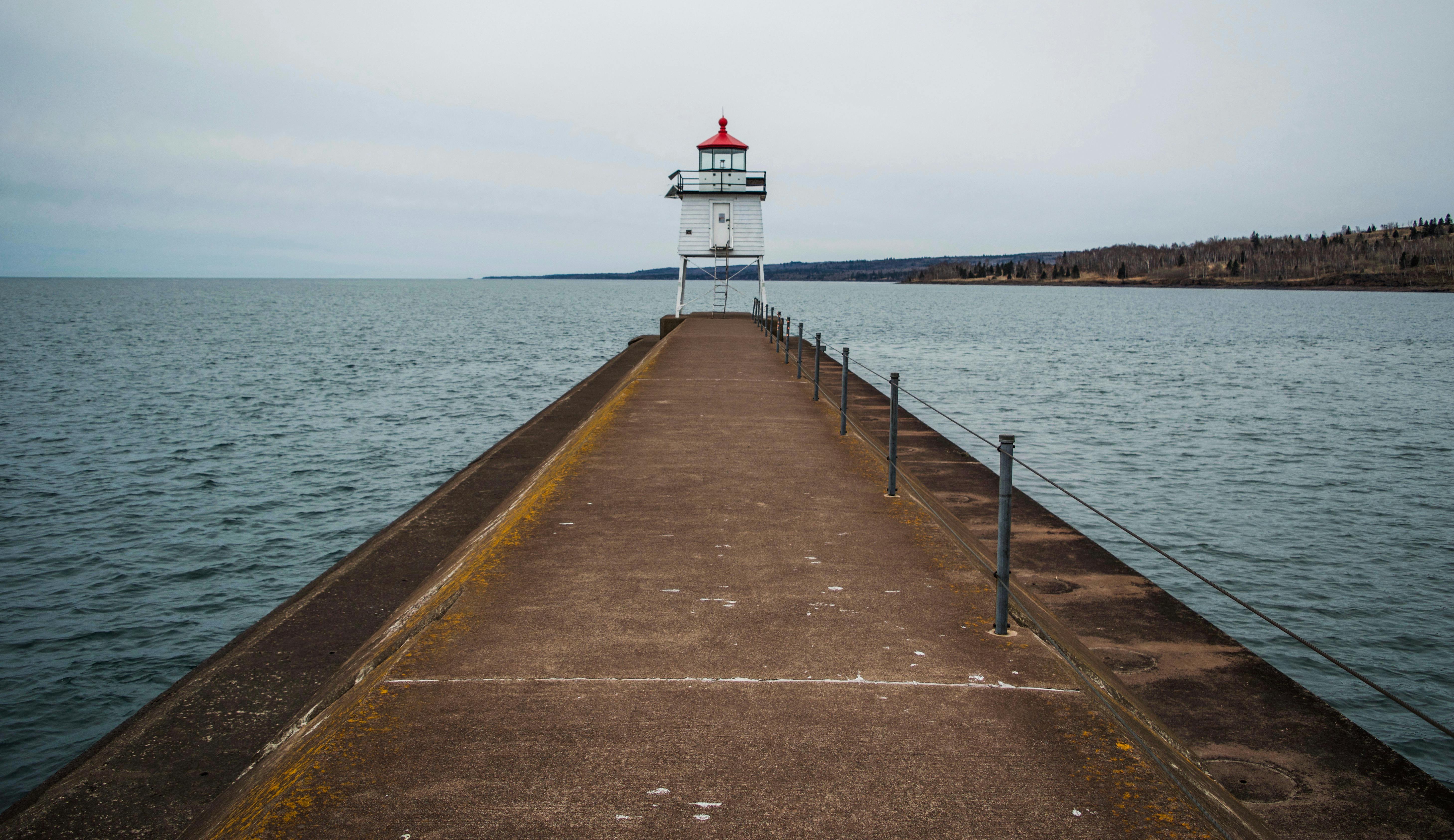 Empty pier with lighthouse in sea · Free Stock Photo