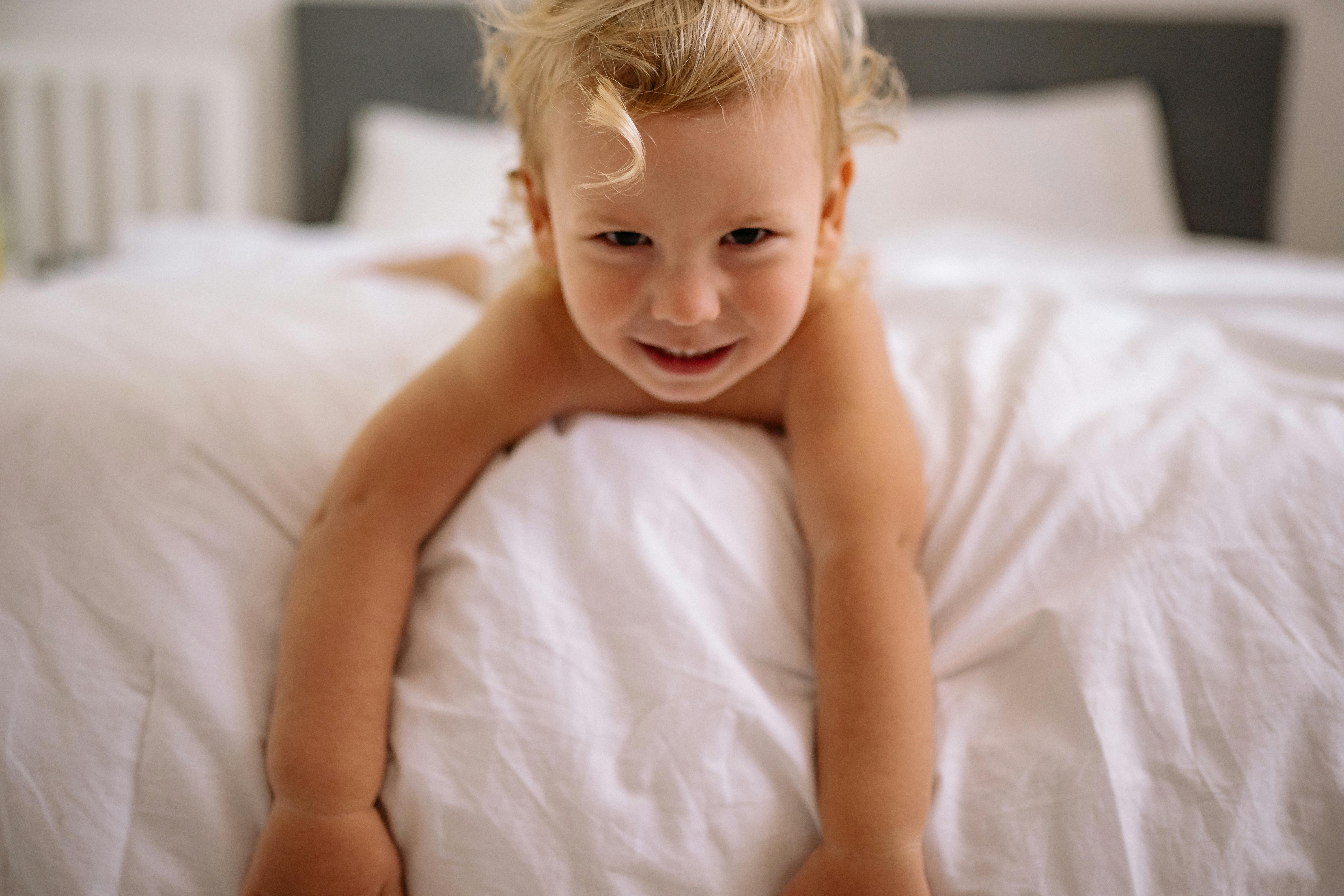 Toddler Lying on White Sheets · Free Stock Photo