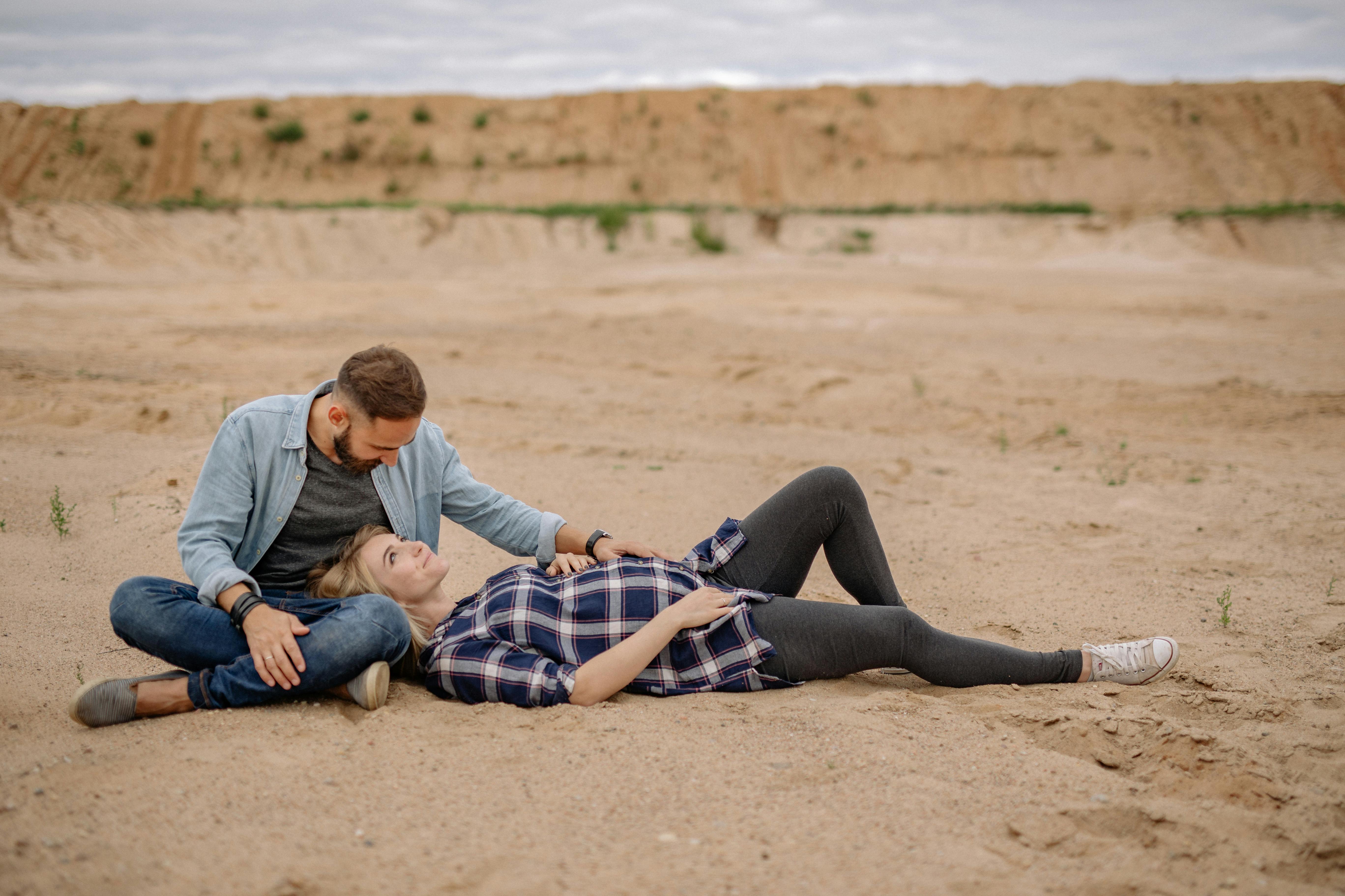 Man Sitting on Sand while Woman Lying on his Lap · Free Stock Photo