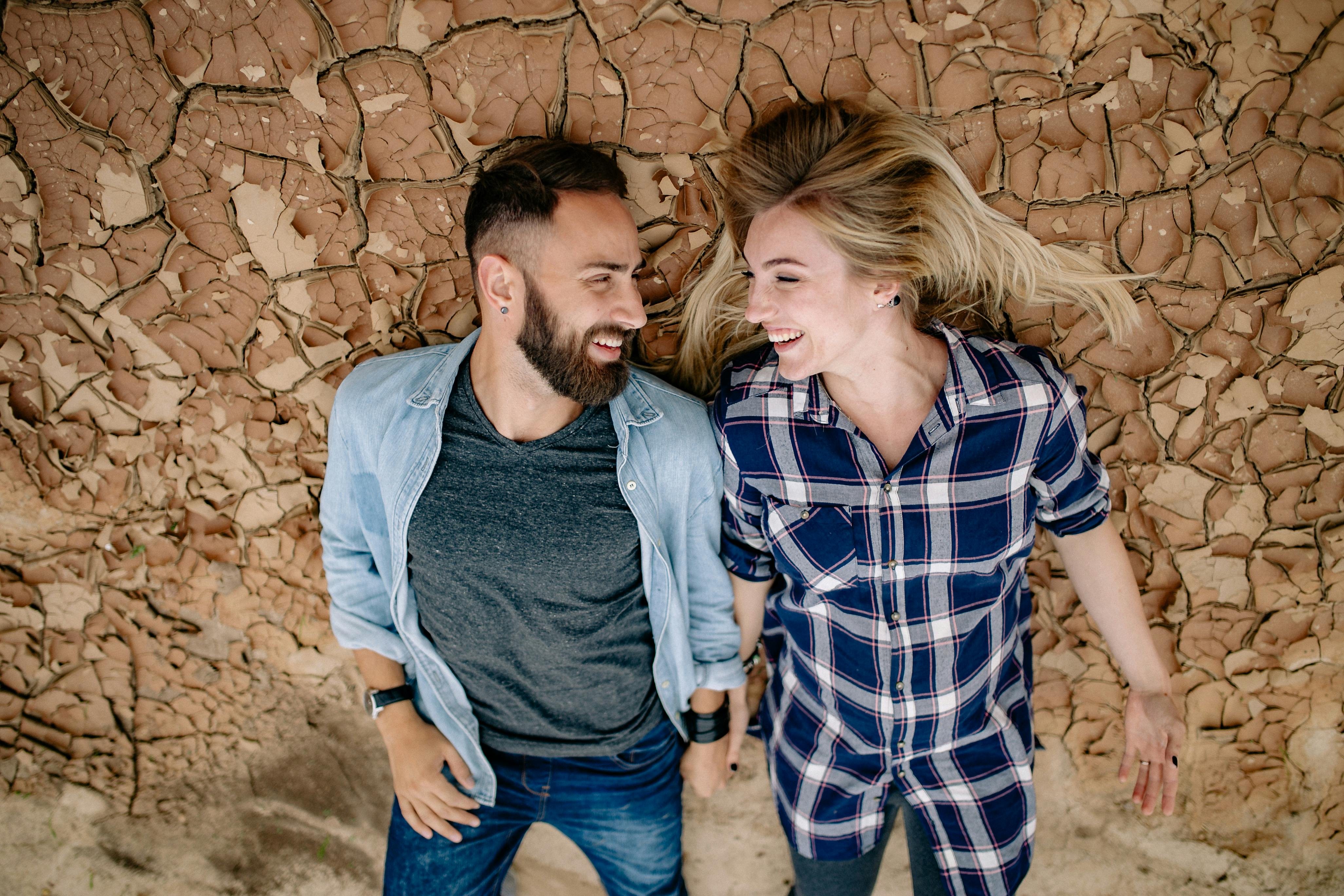 Laughing Couple Lyinng on Dry Ground · Free Stock Photo