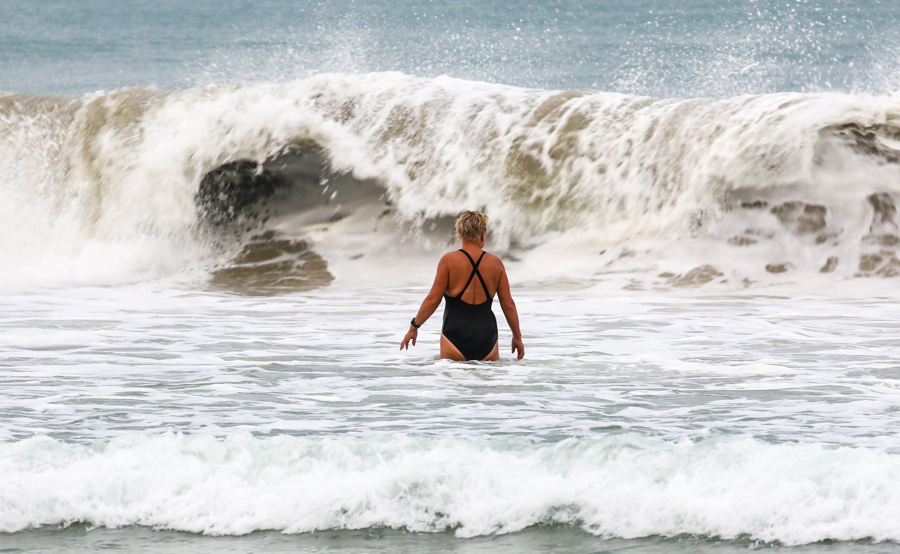 Woman in Black Swimsuit Standing on Beach with Big Waves · Free Stock Photo