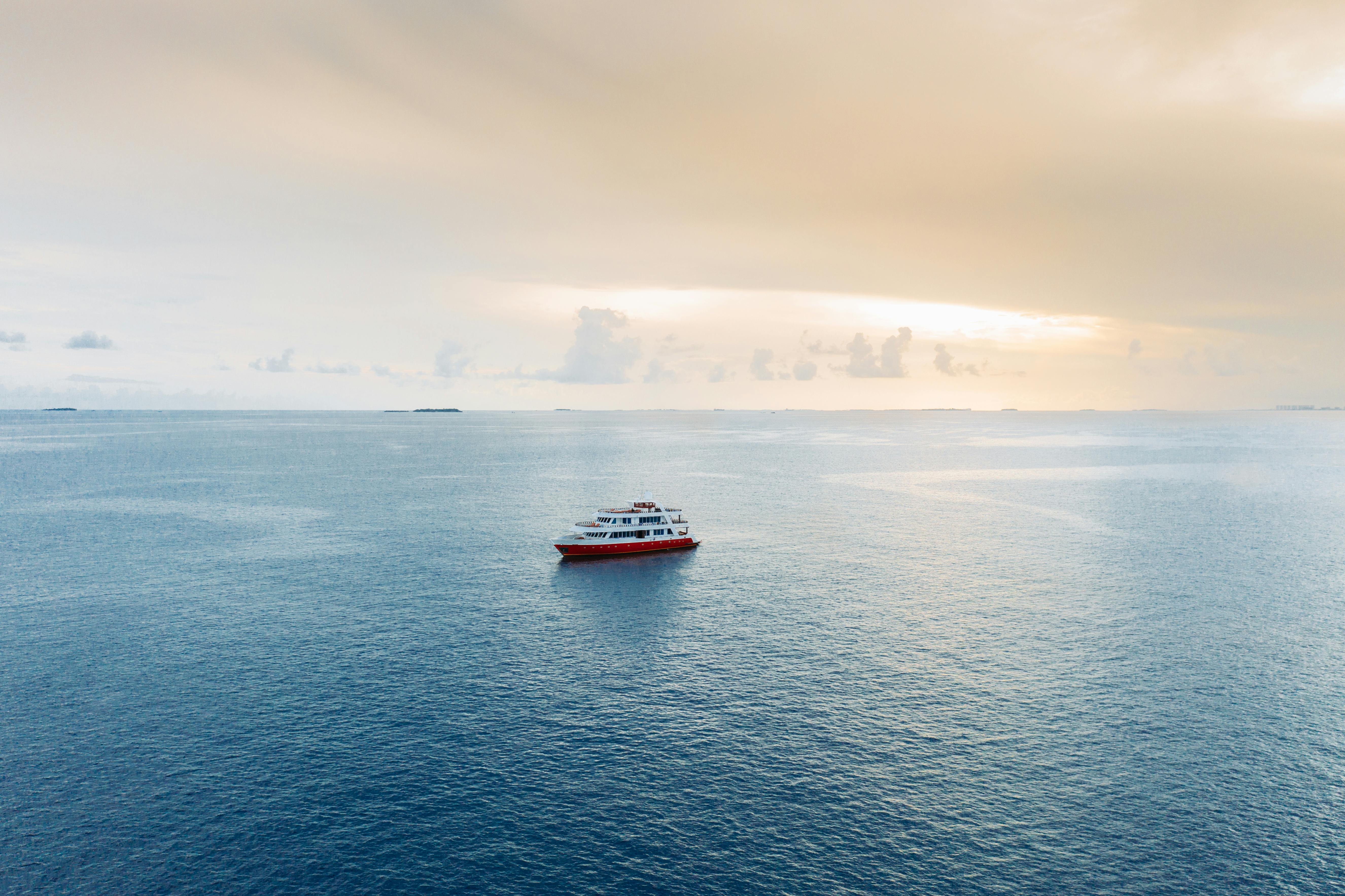 Sailboat floating in sea near rocky cliff · Free Stock Photo