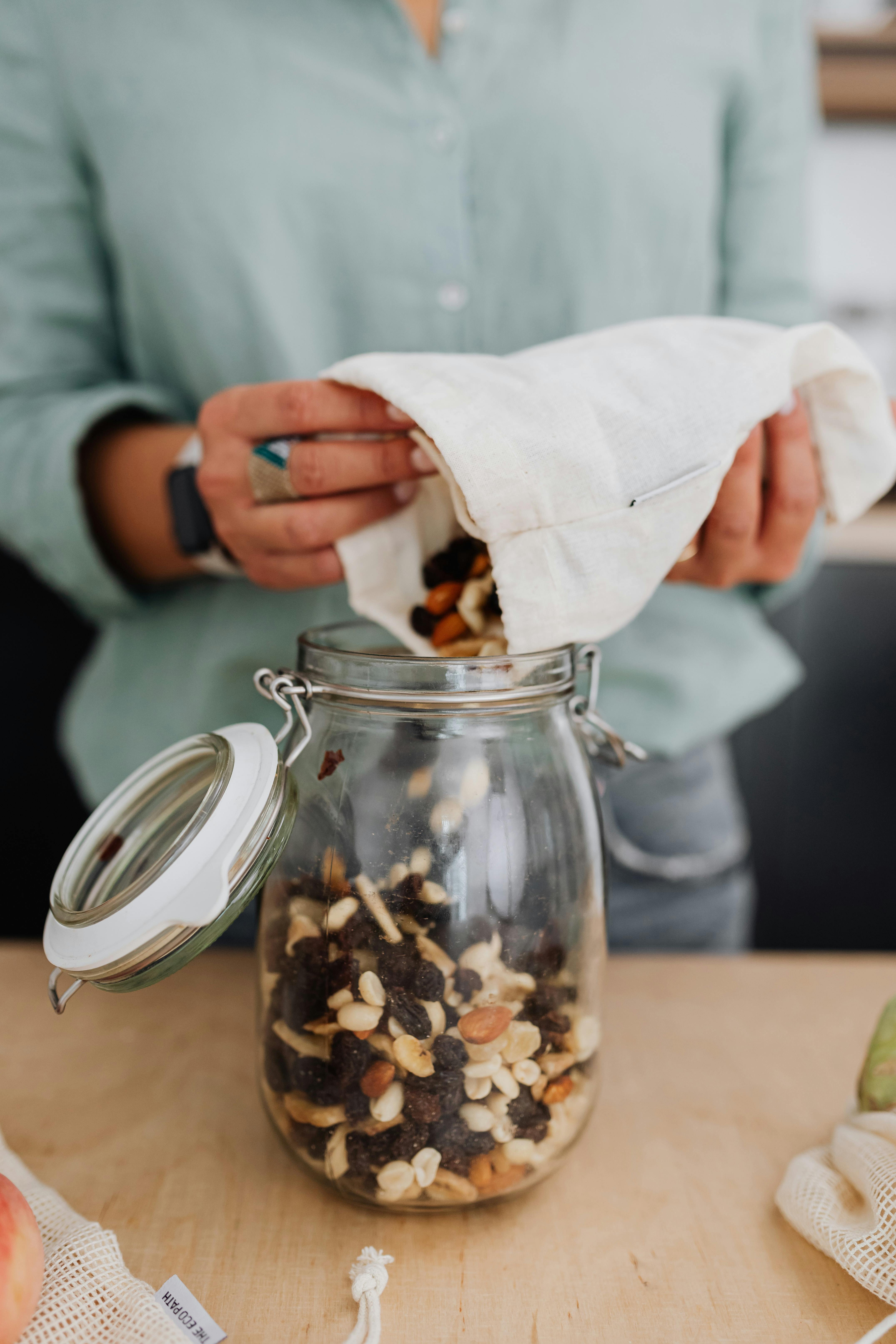 Woman Pouring Nuts and Raisins in Glass Jar · Free Stock Photo