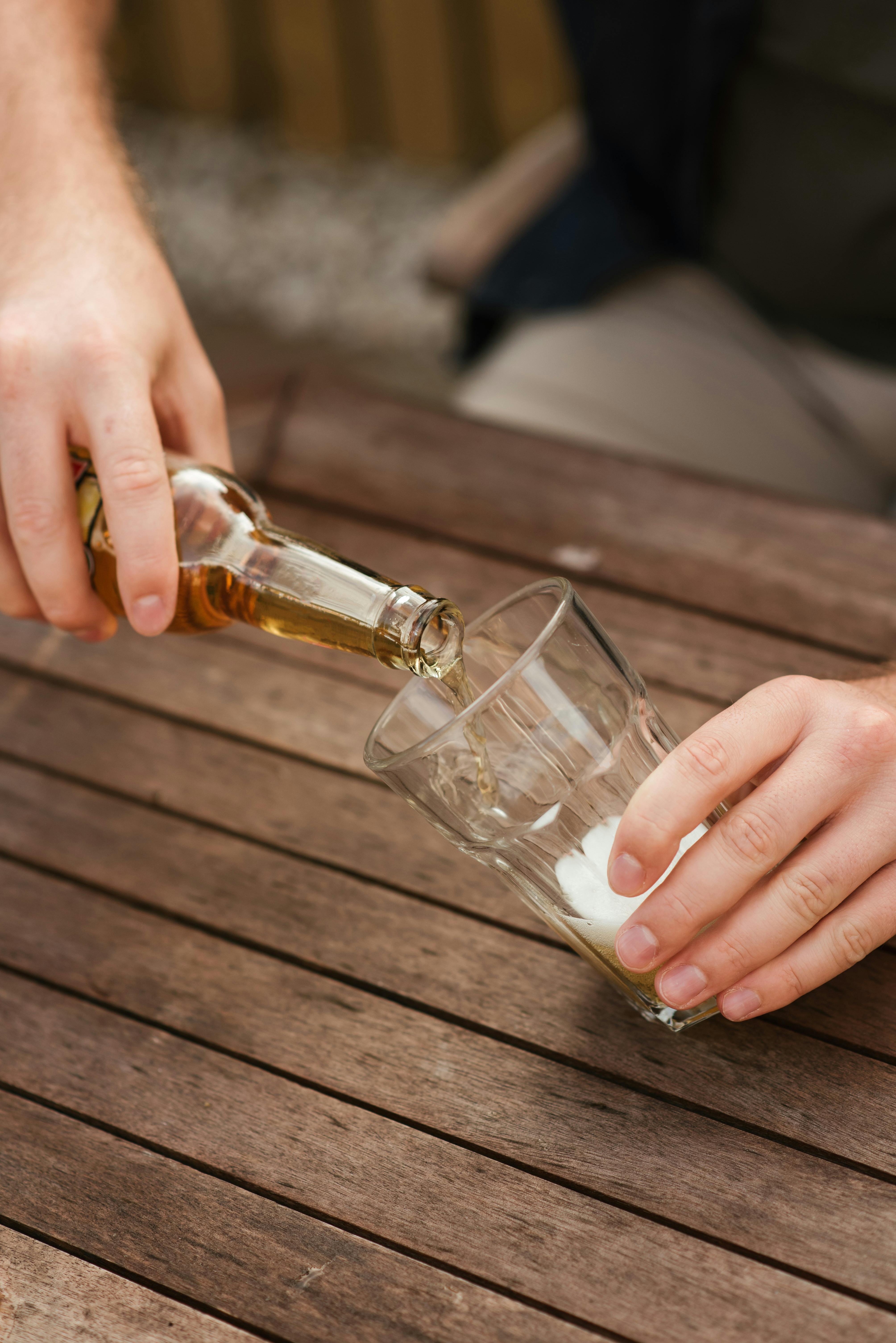 Man filling glass cup with foaming beer · Free Stock Photo
