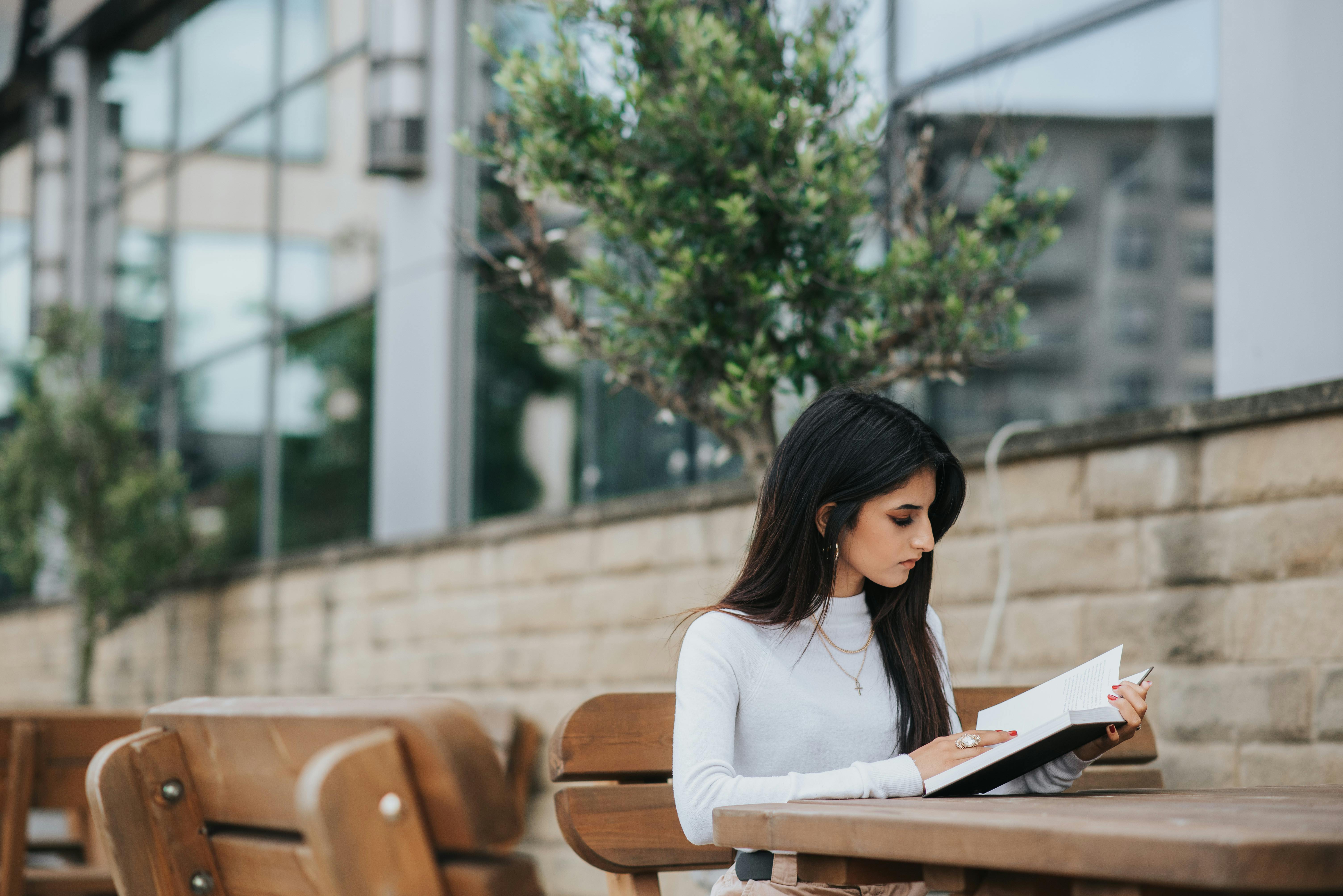 Happy adult woman reading book with interest on street · Free Stock Photo