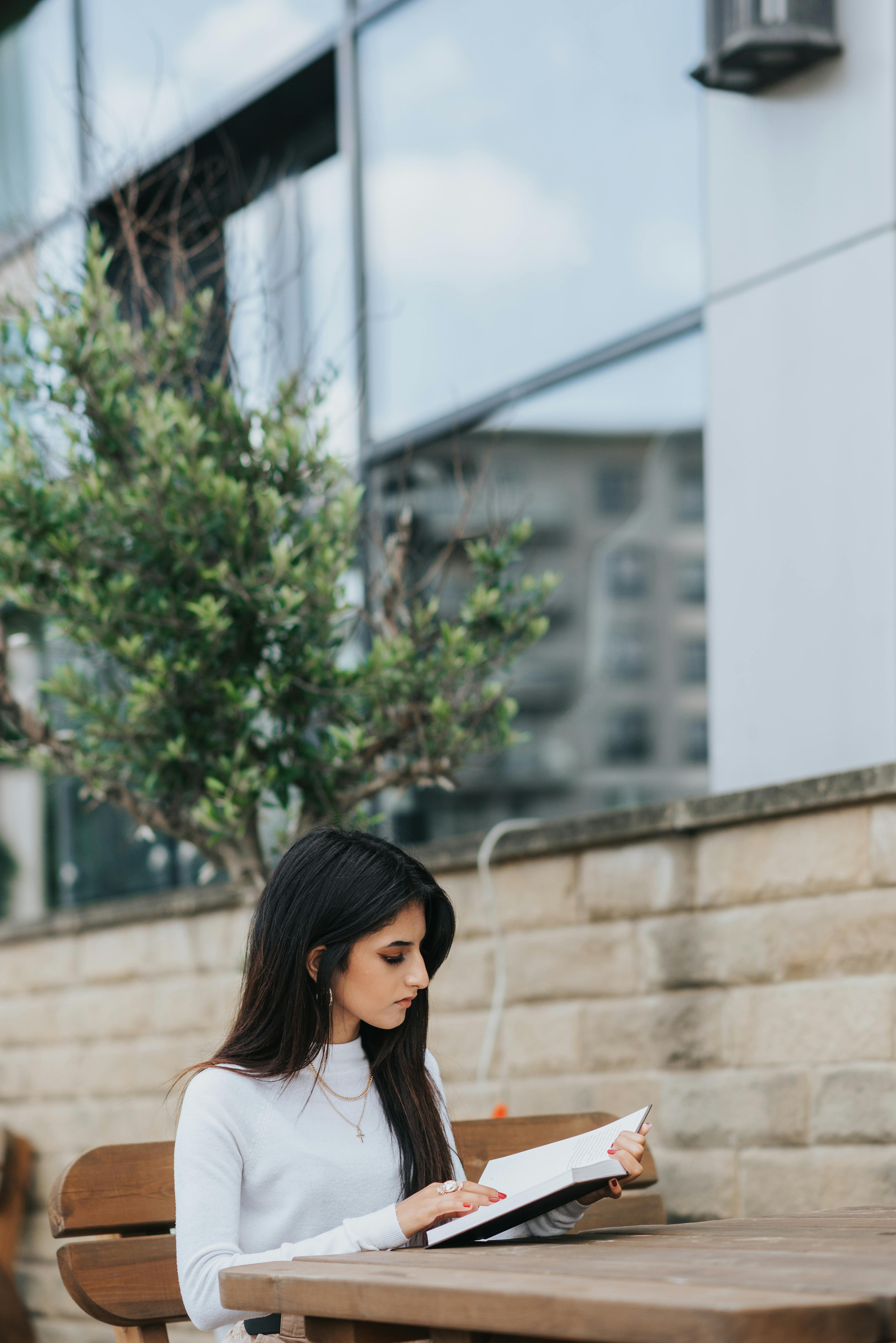 Pensive ethnic woman reading book on street · Free Stock Photo