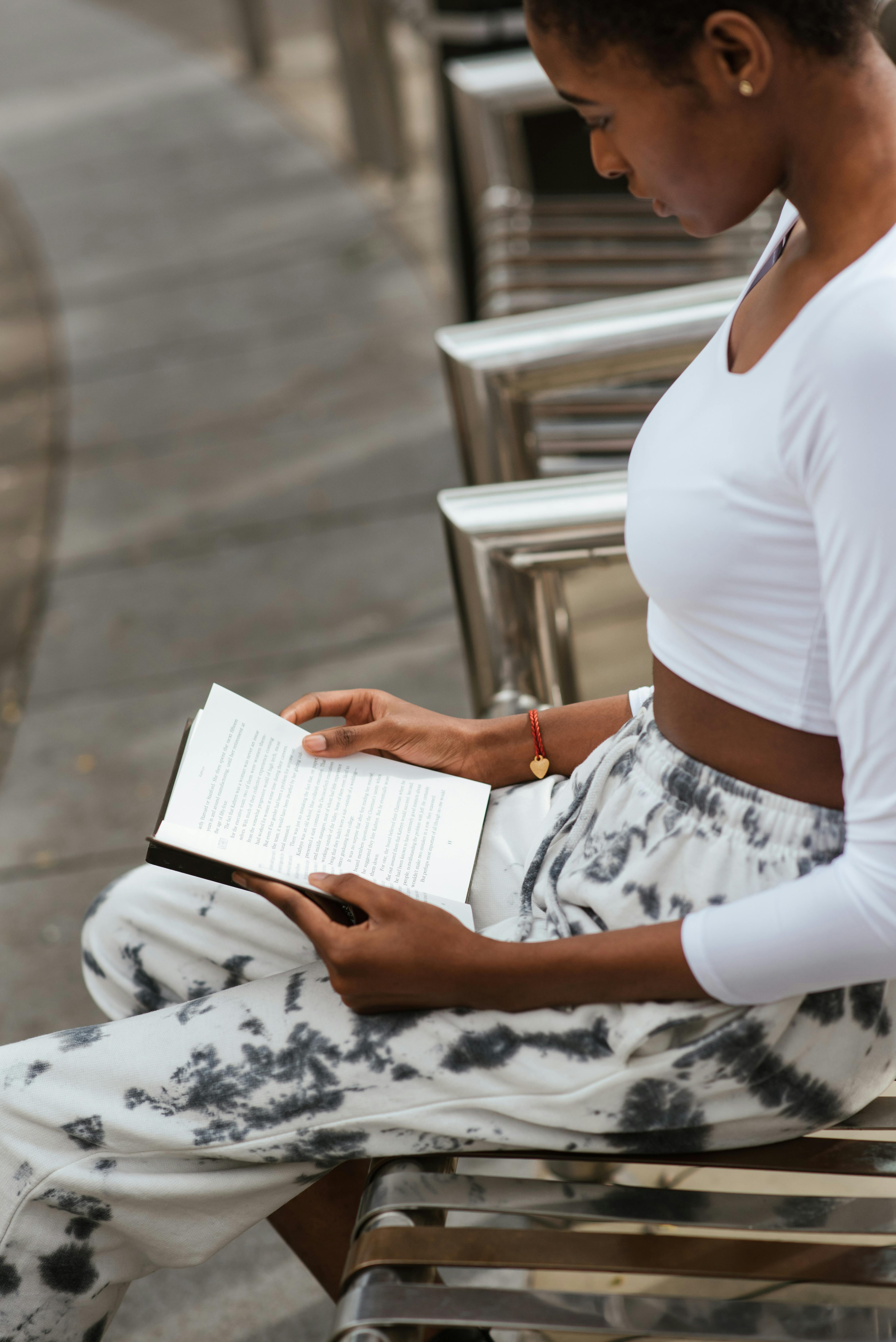 Black woman reading book on city street · Free Stock Photo