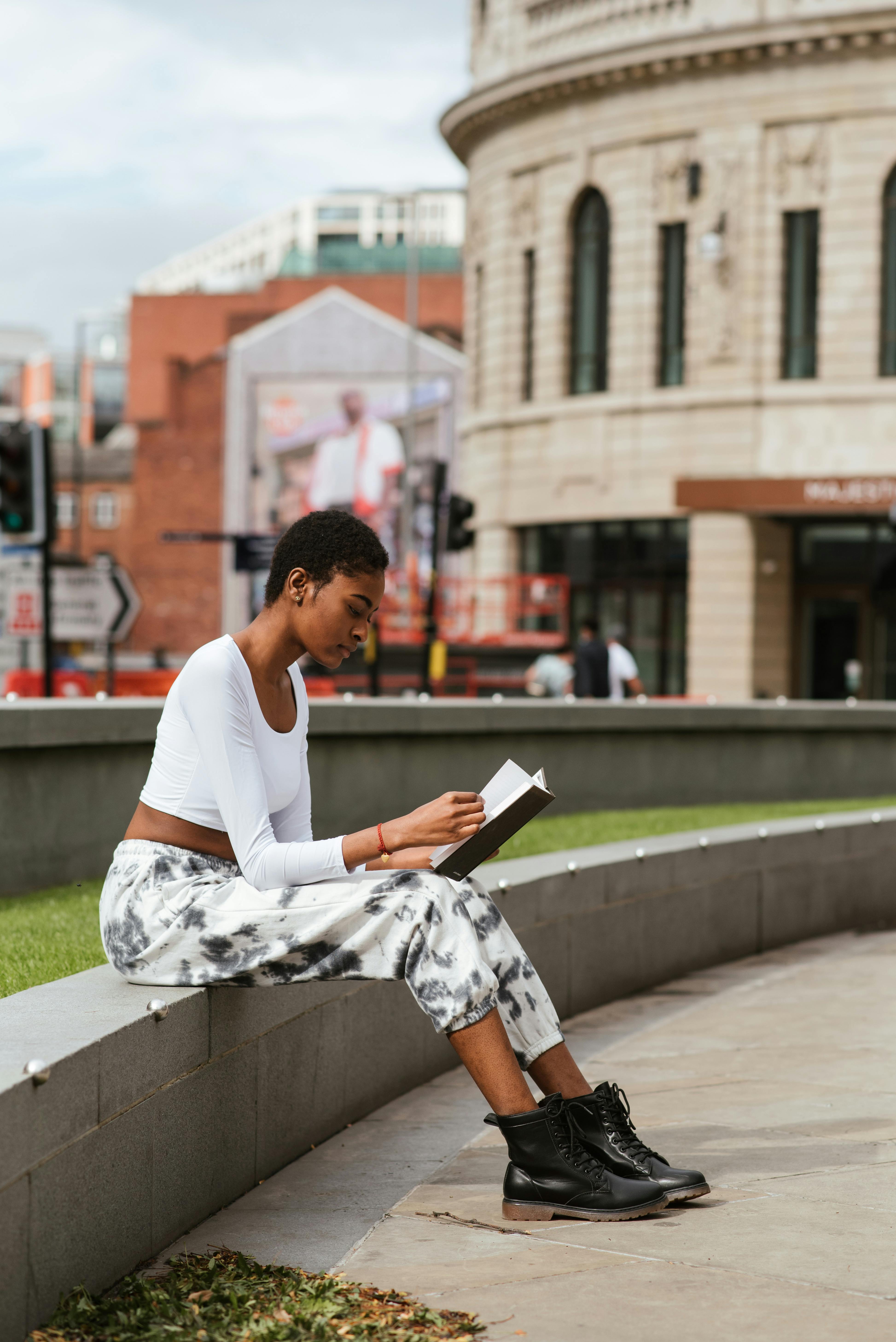 Black woman reading book on city street · Free Stock Photo