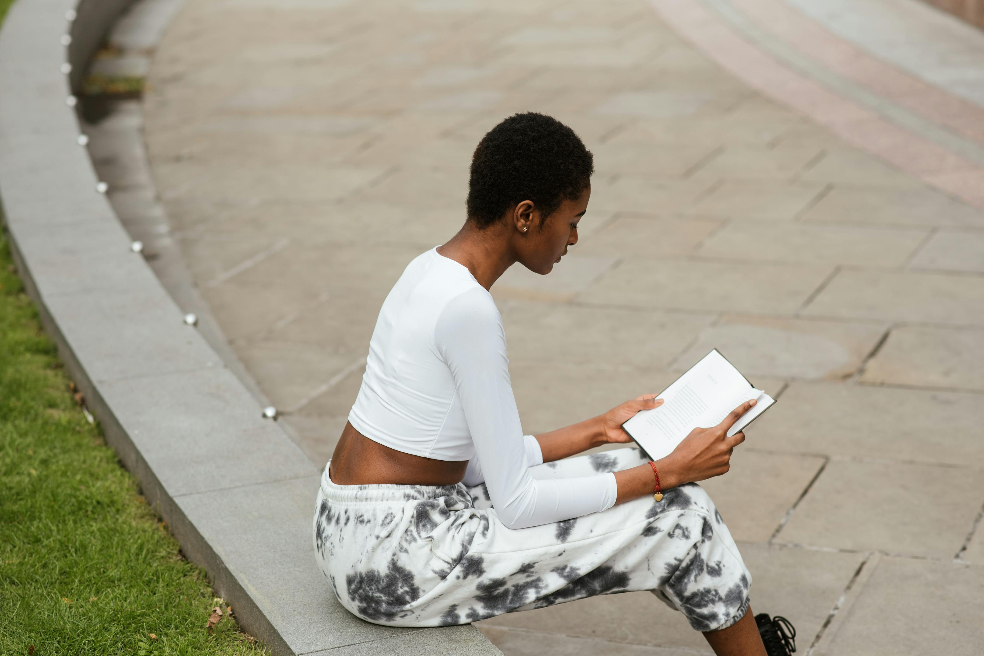 Focused African American Woman Reading Textbook On Street · Free Stock