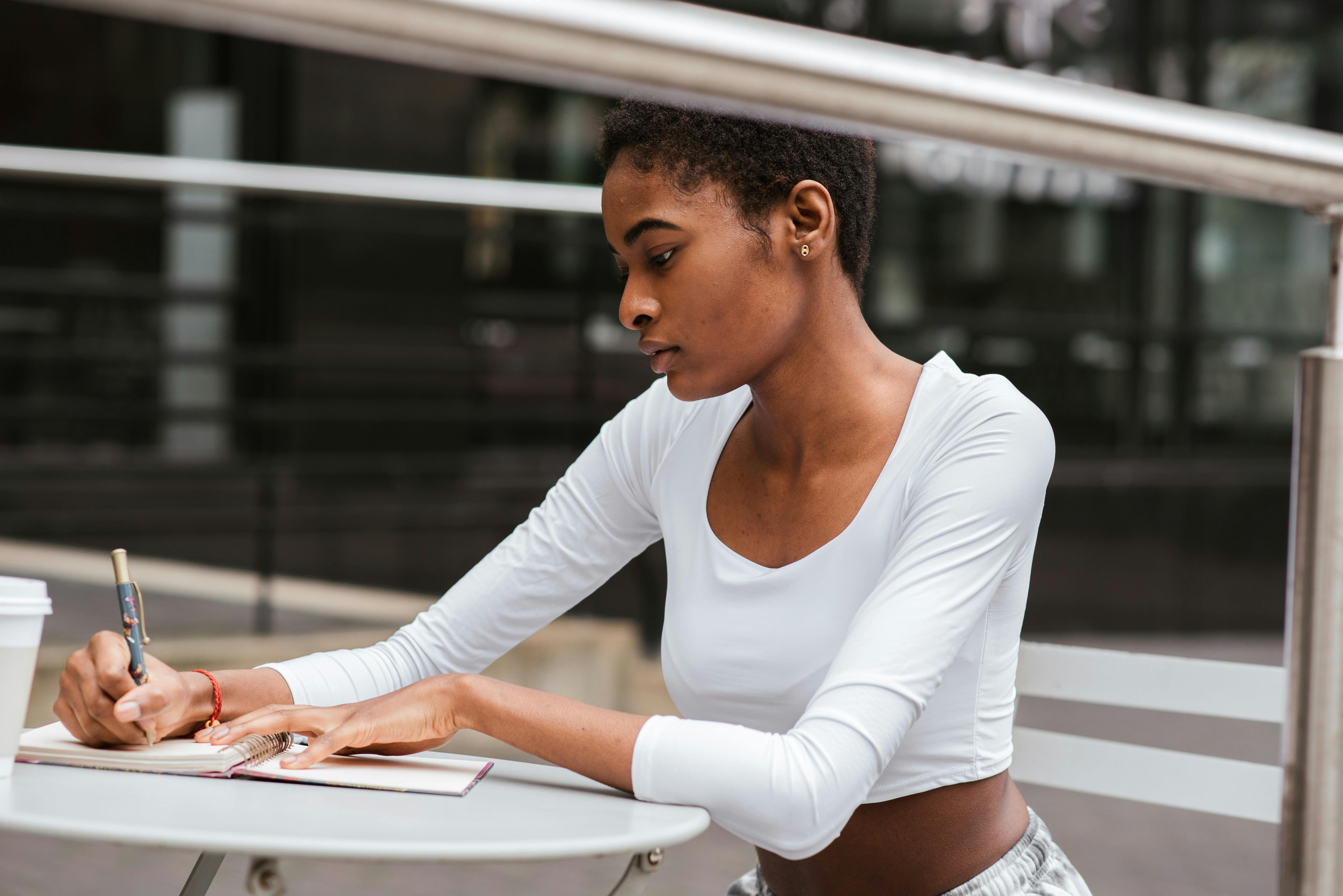 Serious black woman writing notes in planner · Free Stock Photo