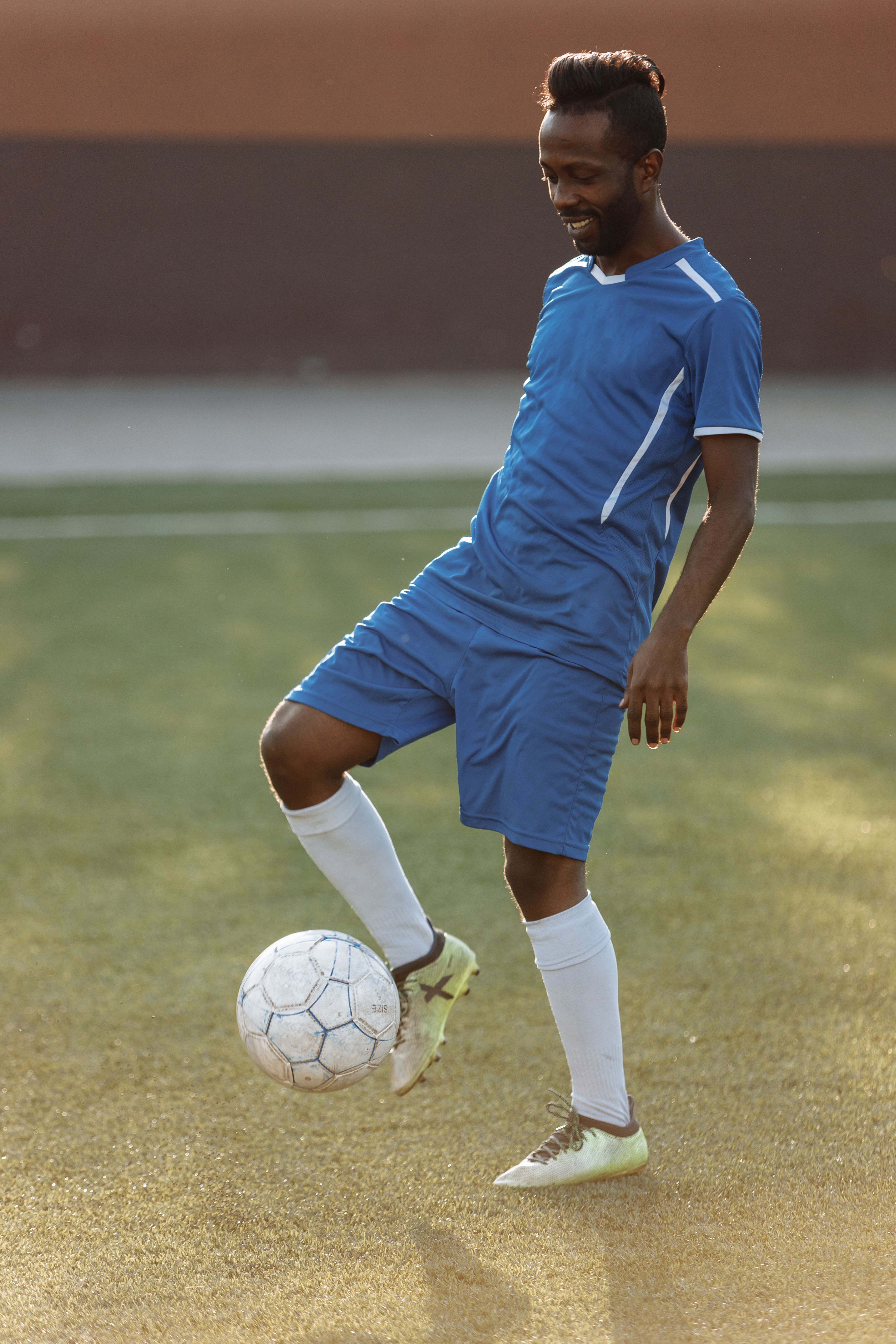 Young black man kicking ball on sandy beach · Free Stock Photo