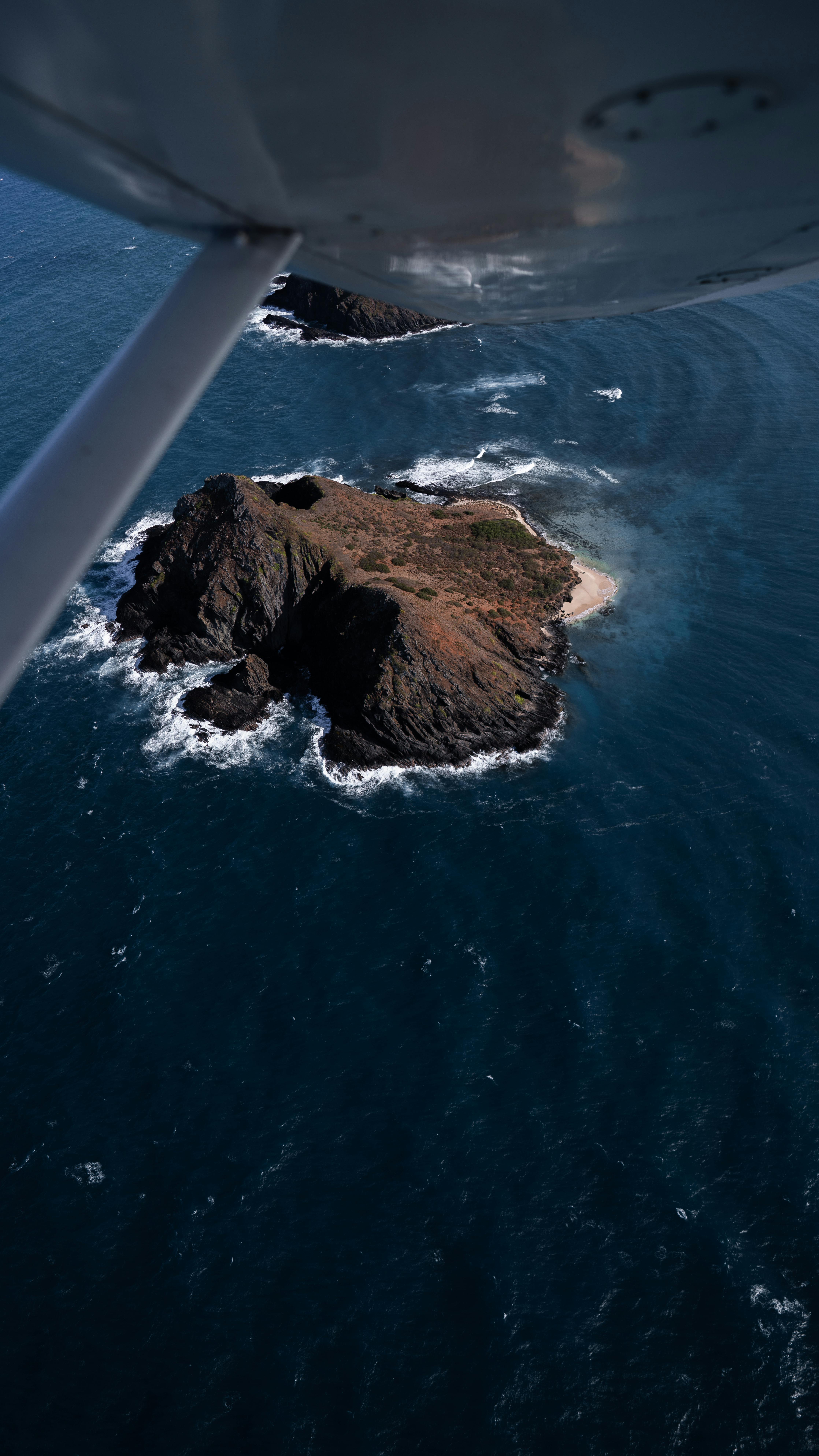 Volcanic island with sandy beach in blue sea · Free Stock Photo