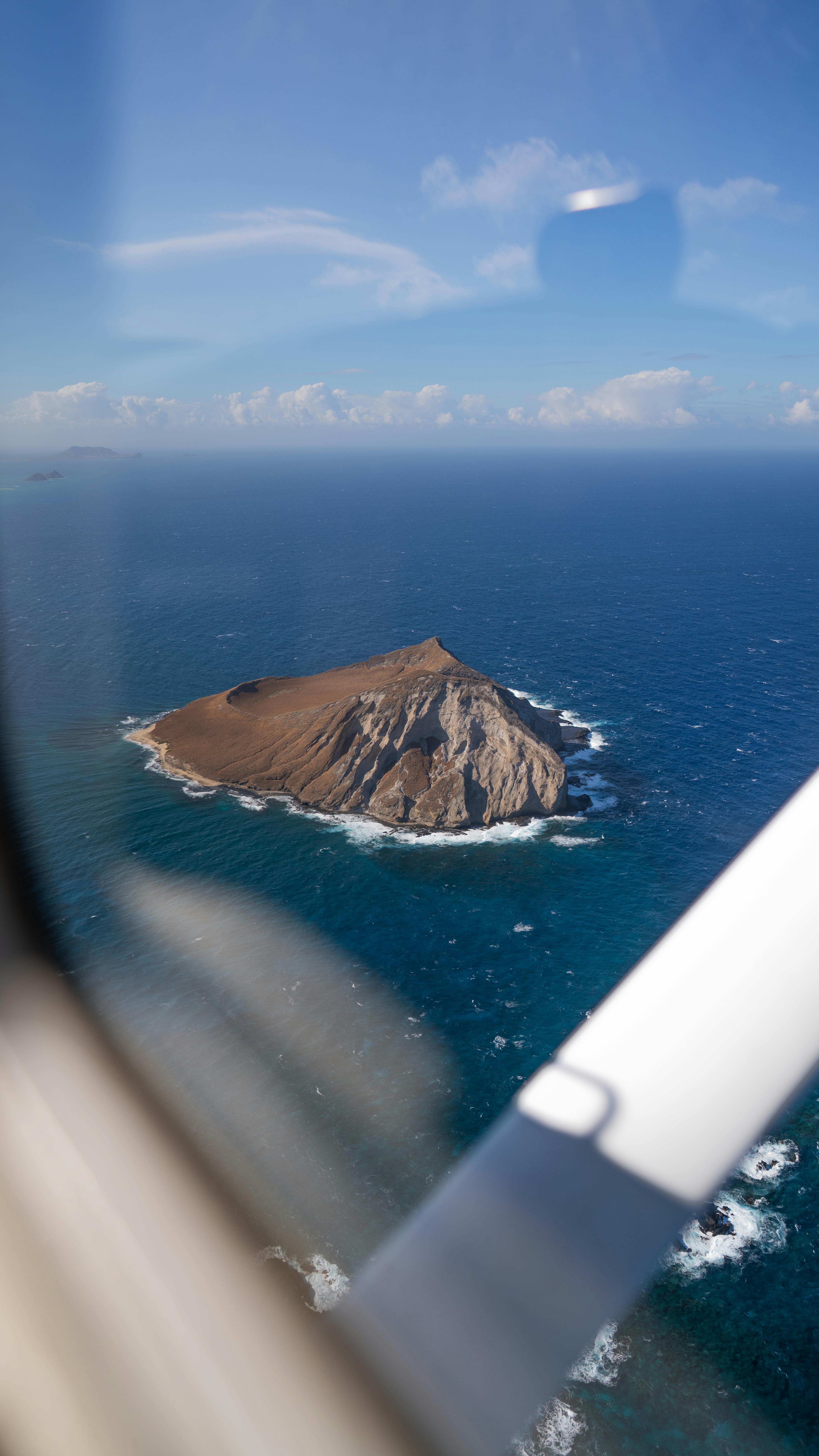 Volcanic island with sandy beach in blue sea · Free Stock Photo