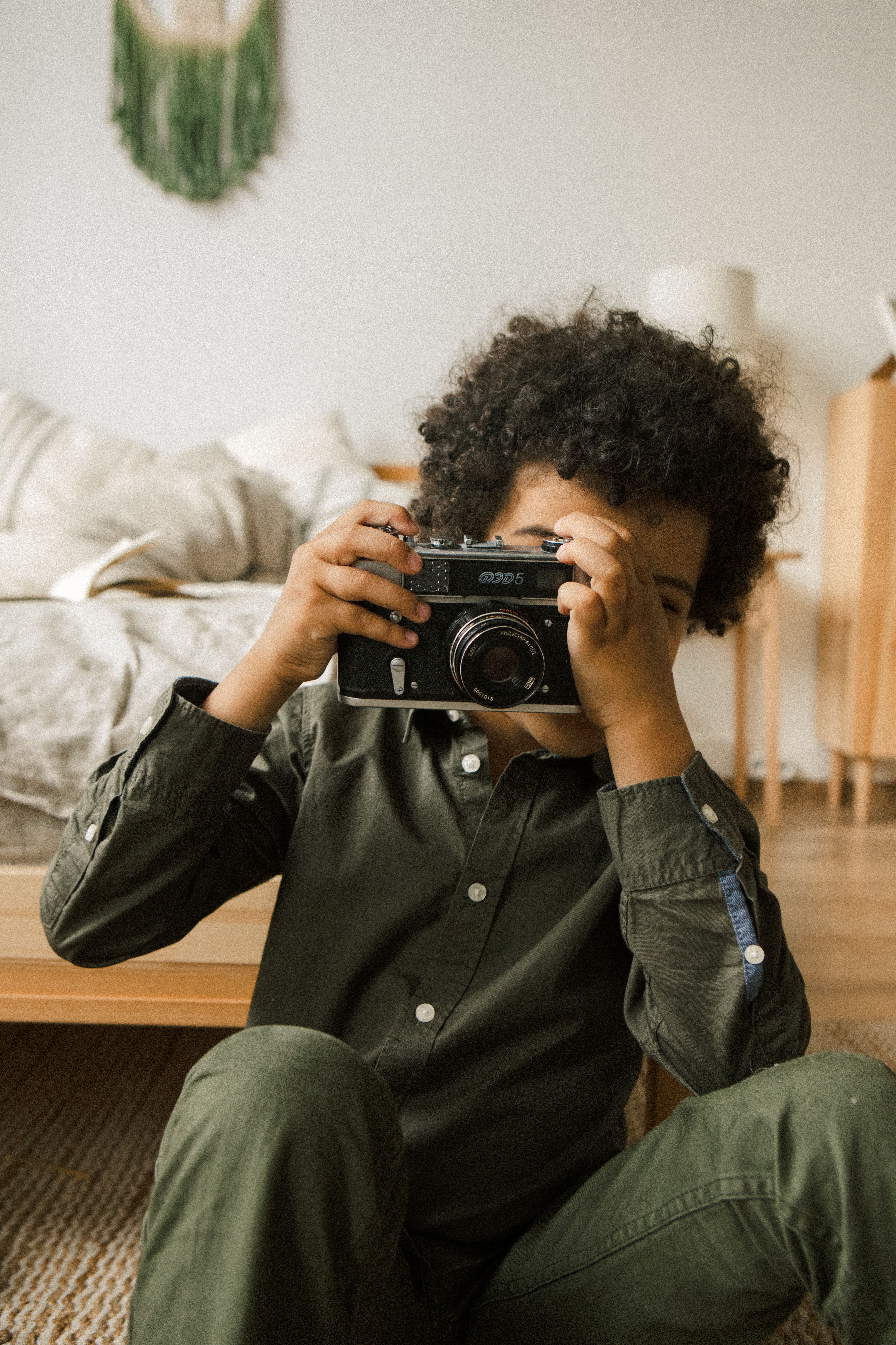 Little Boy Sitting in a Bedroom and Taking a Picture with a Camera ...