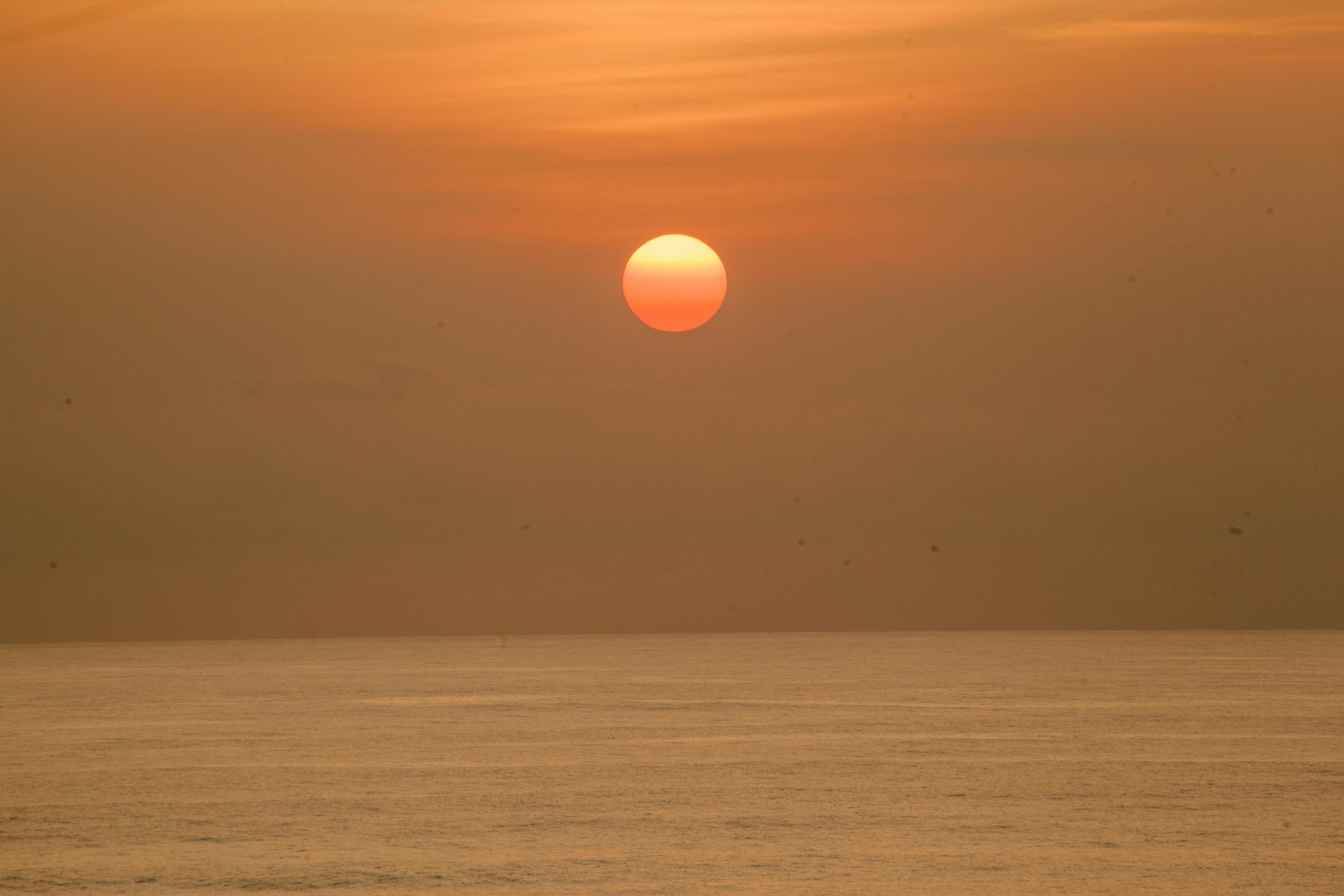 Sun setting over calm rippling sea · Free Stock Photo