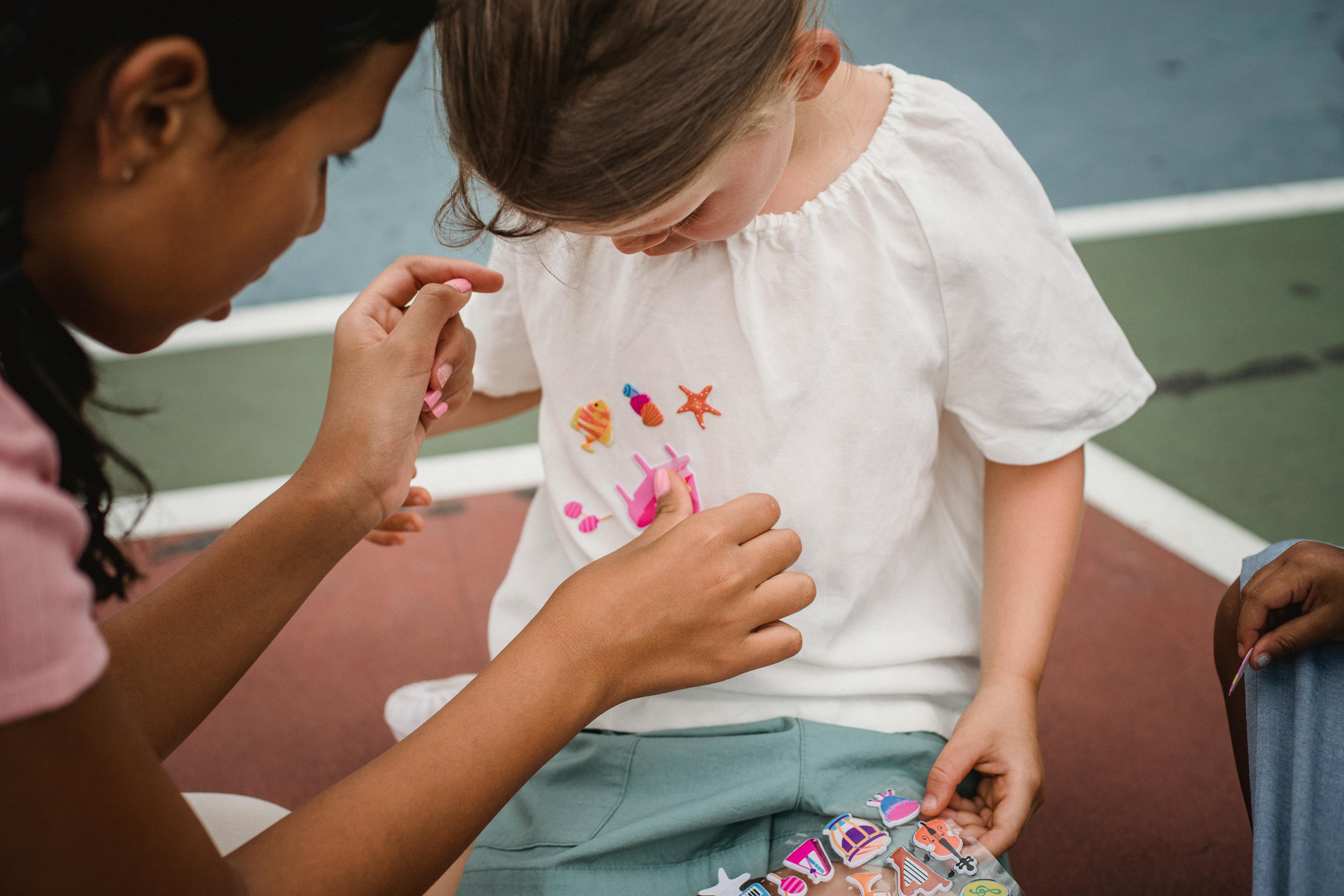 Girl Putting a Sticker on a Shirt · Free Stock Photo
