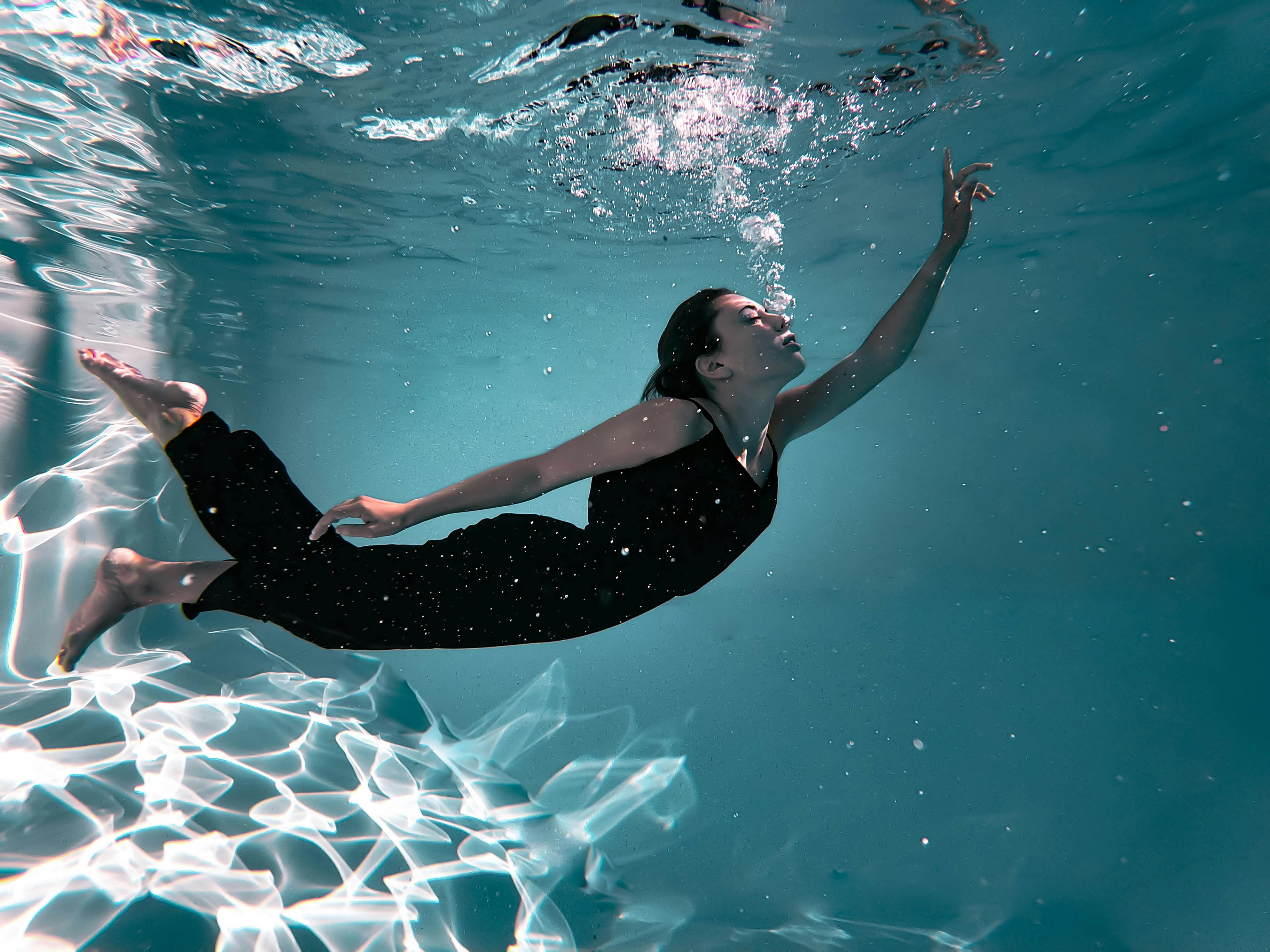 Peaceful young woman submerged in sea water on sunny day · Free Stock Photo