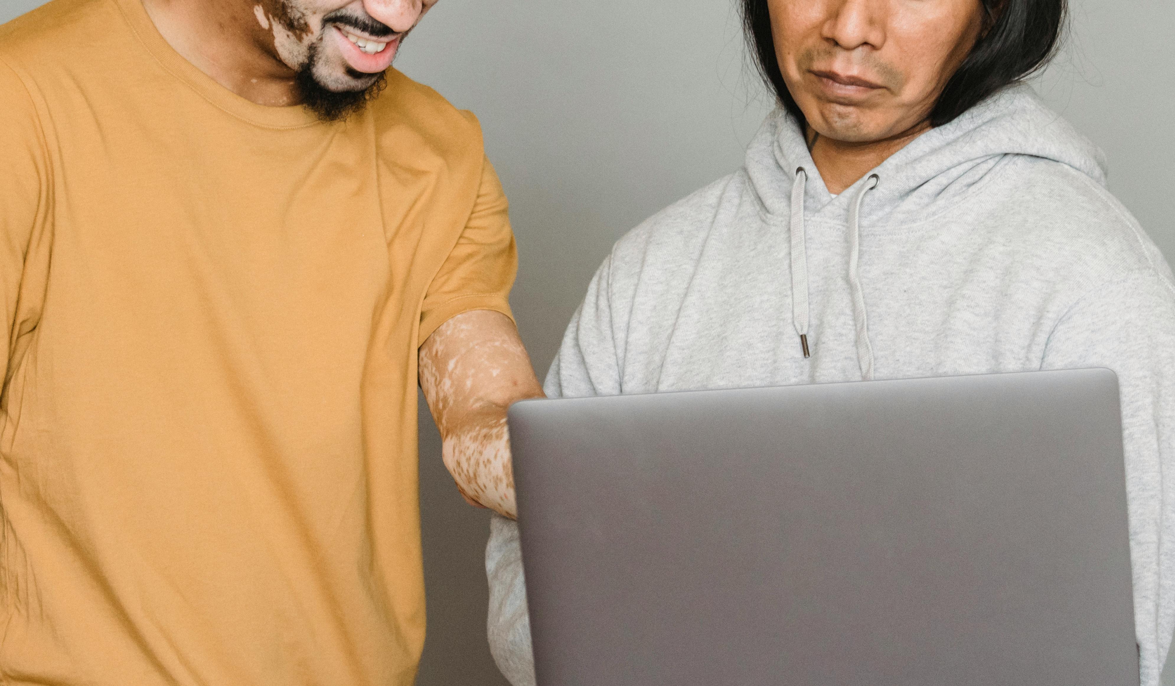 Positive black man with vitiligo working online with ethnic colleague ...