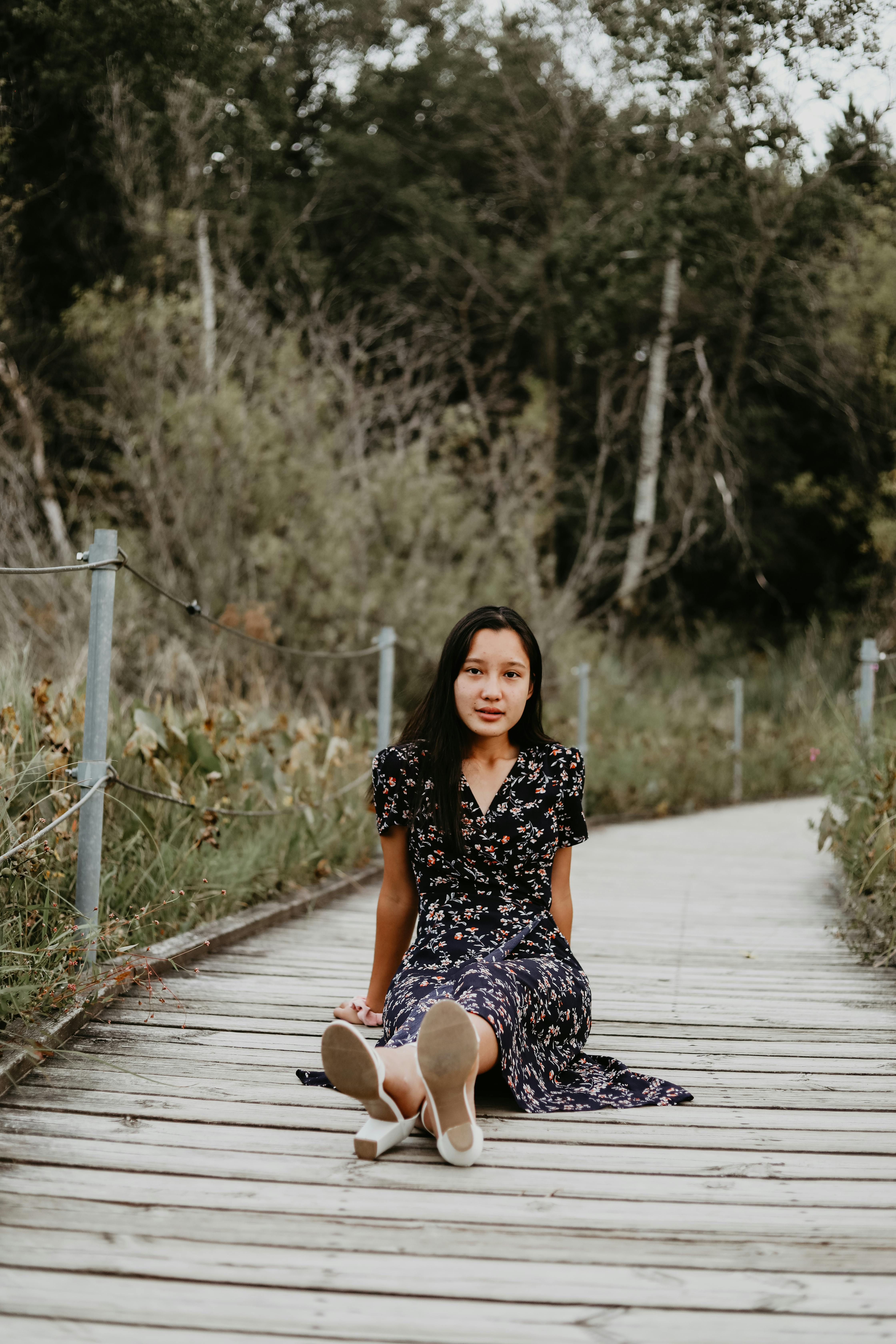 Stylish Asian woman sitting on boardwalk · Free Stock Photo