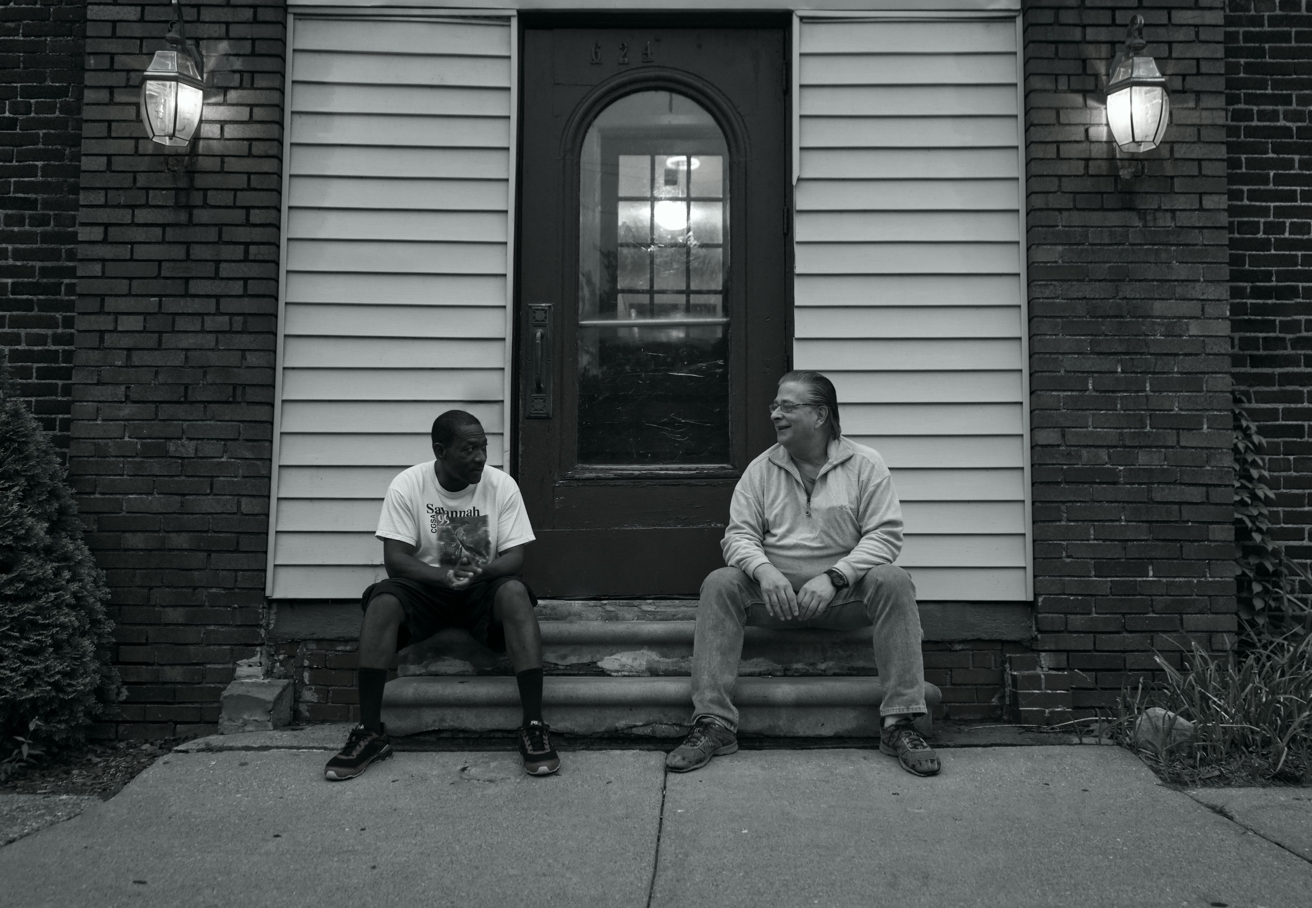 Diverse happy friends talking on steps of modern house · Free Stock Photo