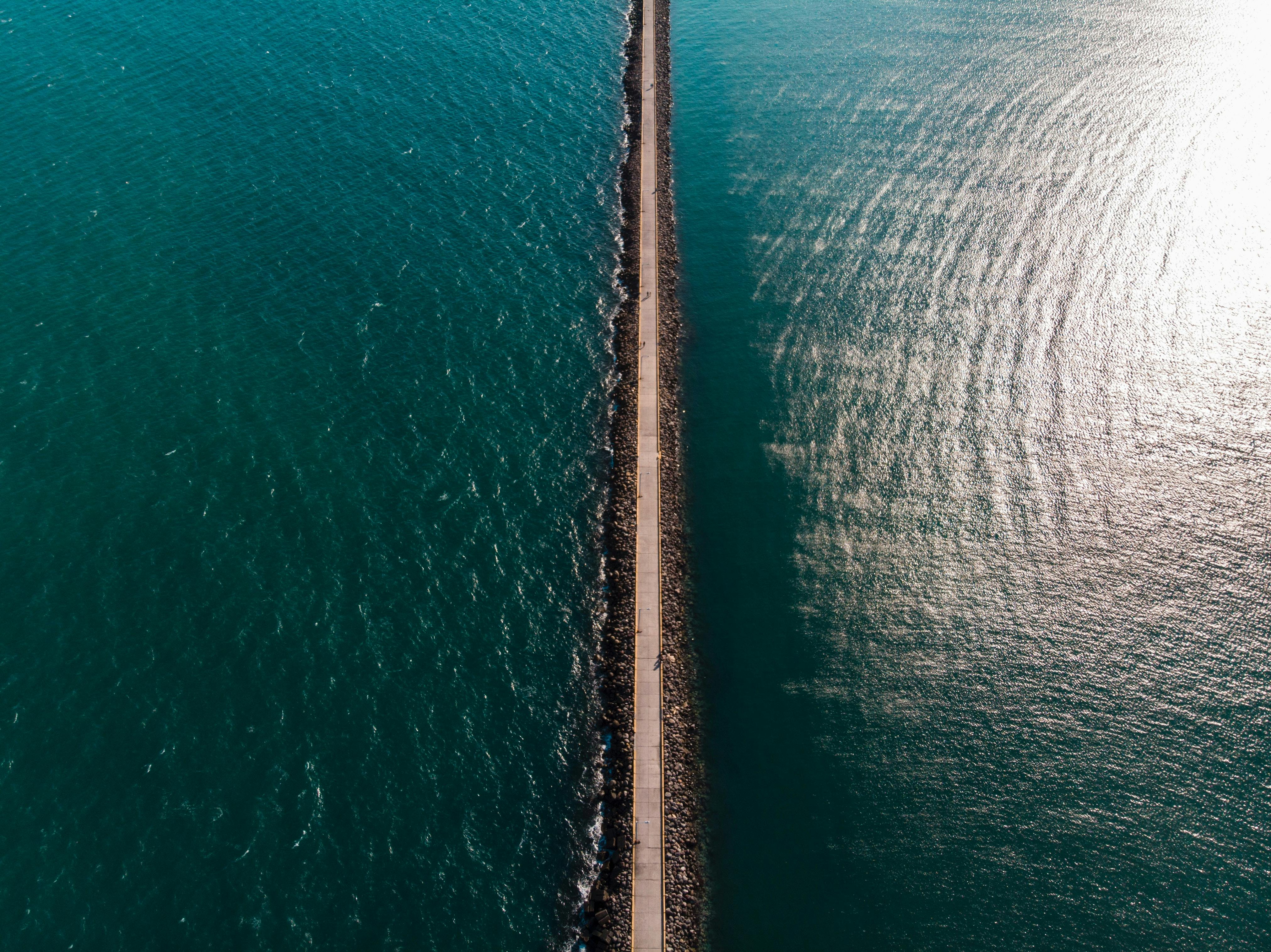 An Aerial Photography of a Road Between Body of Water · Free Stock Photo