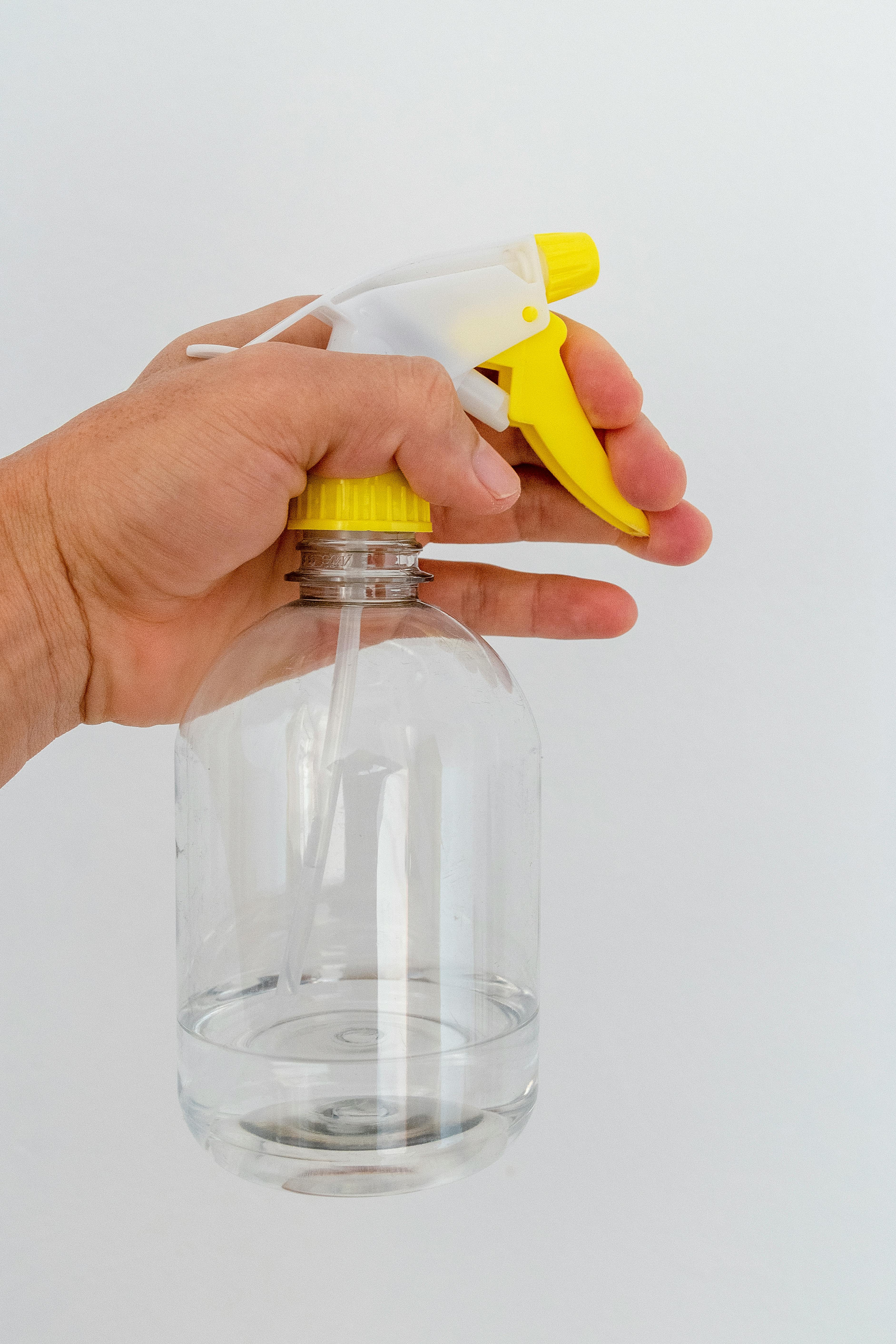 Person Holding a White and Yellow Spray Bottle · Free Stock Photo