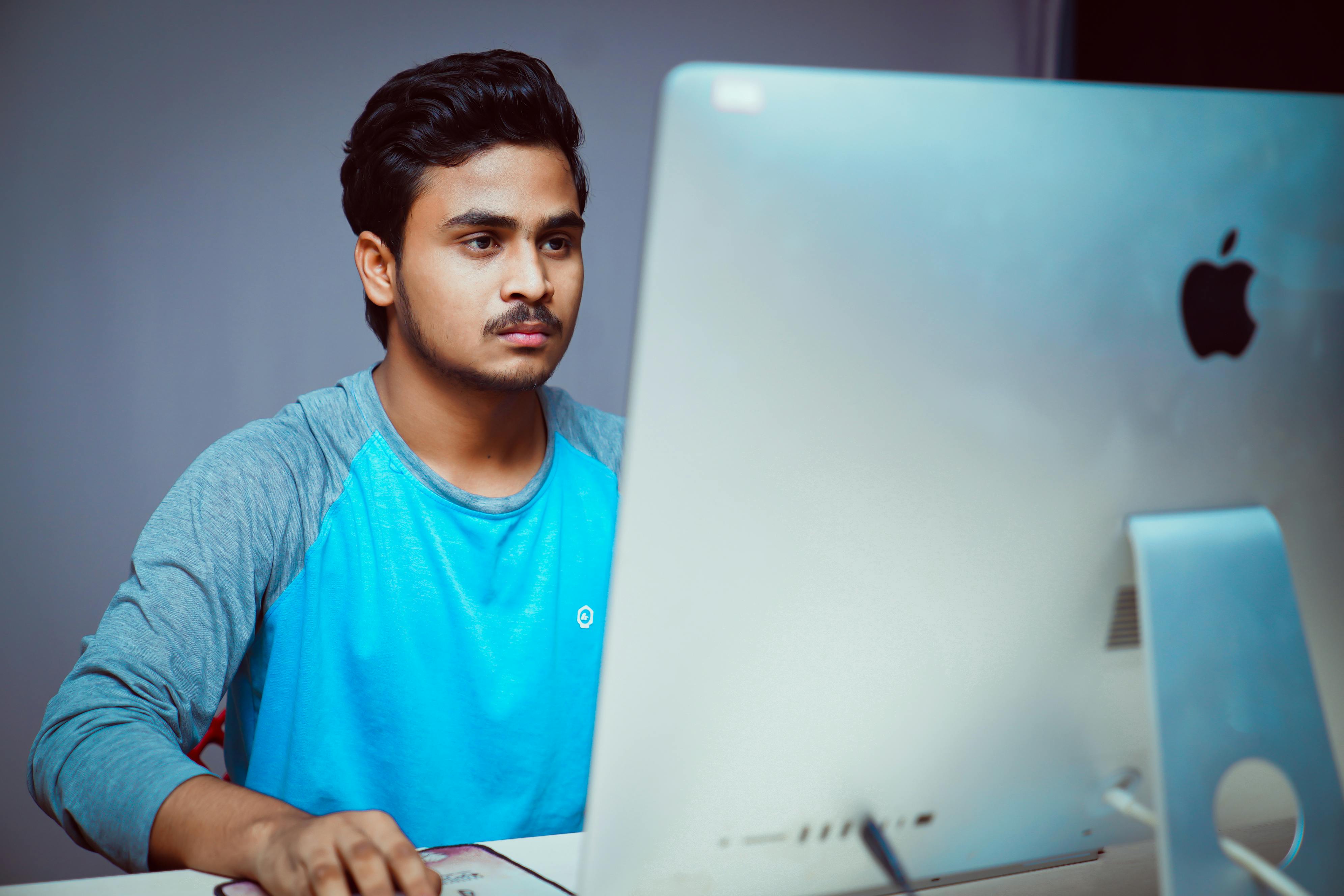 Man Wearing Blue Sweater Using a Computer · Free Stock Photo