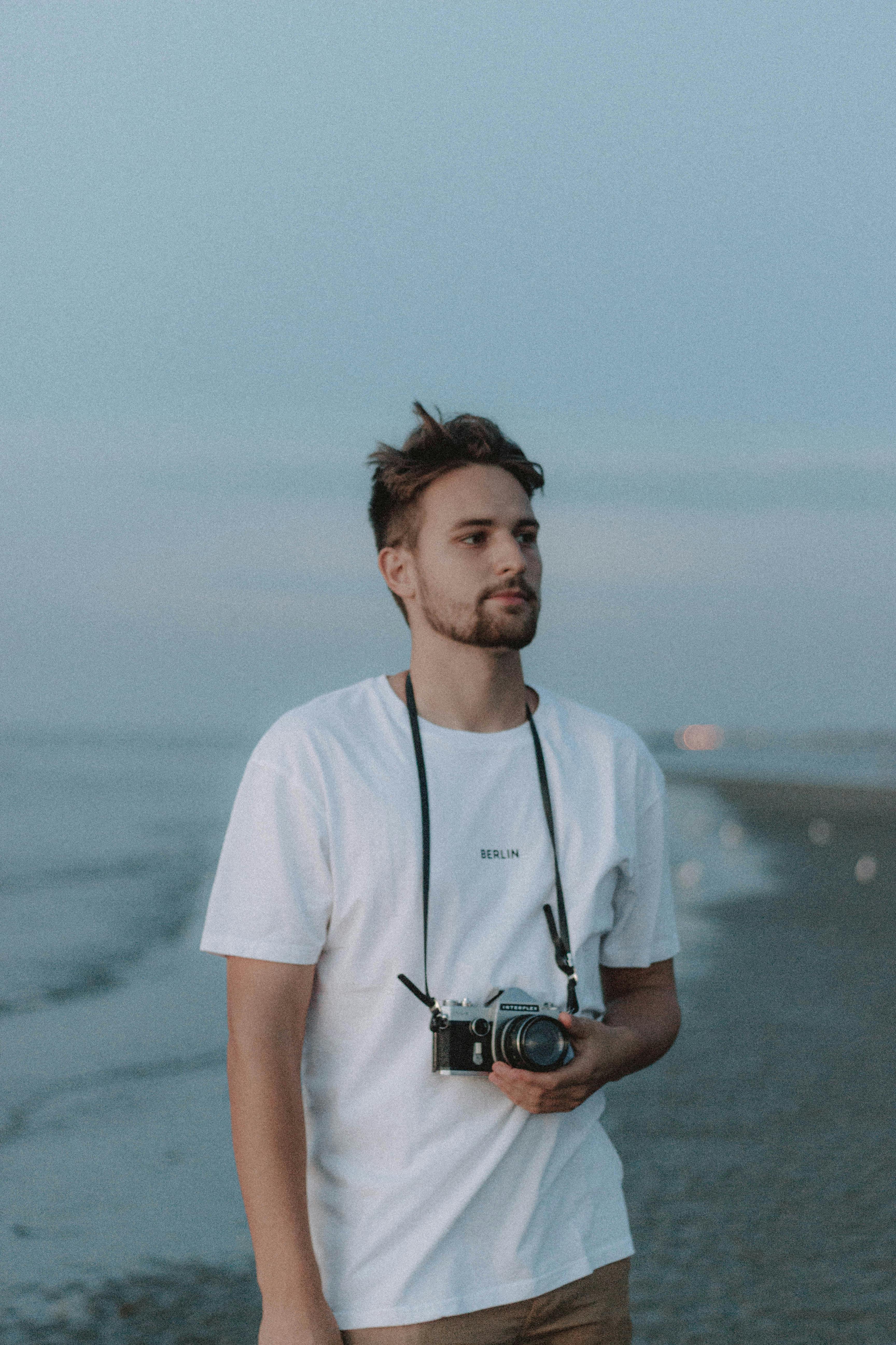 Stylish man model standing on sandy coast near sea · Free Stock Photo