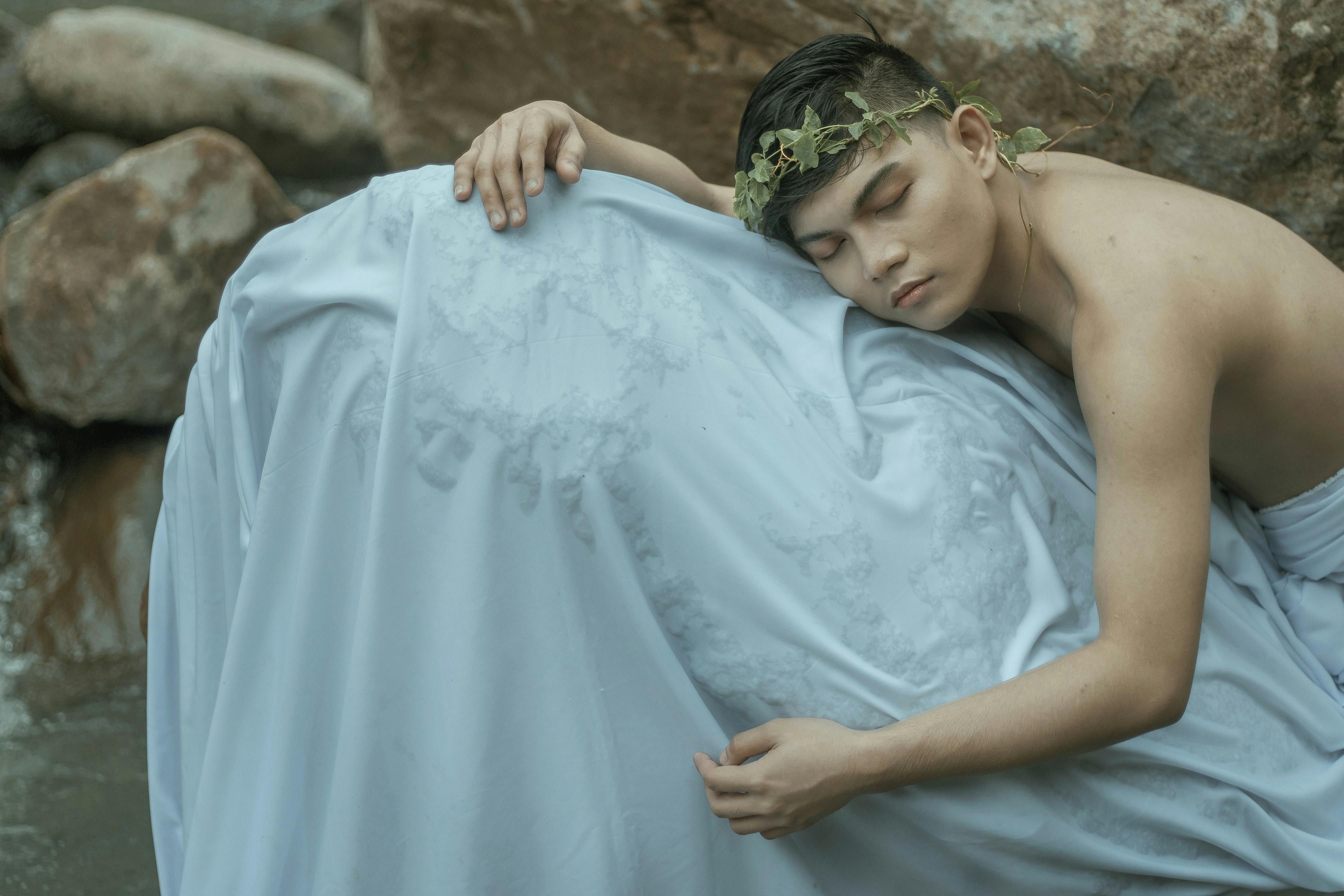 Young man as ancient Greek outfit resting on stones · Free Stock Photo