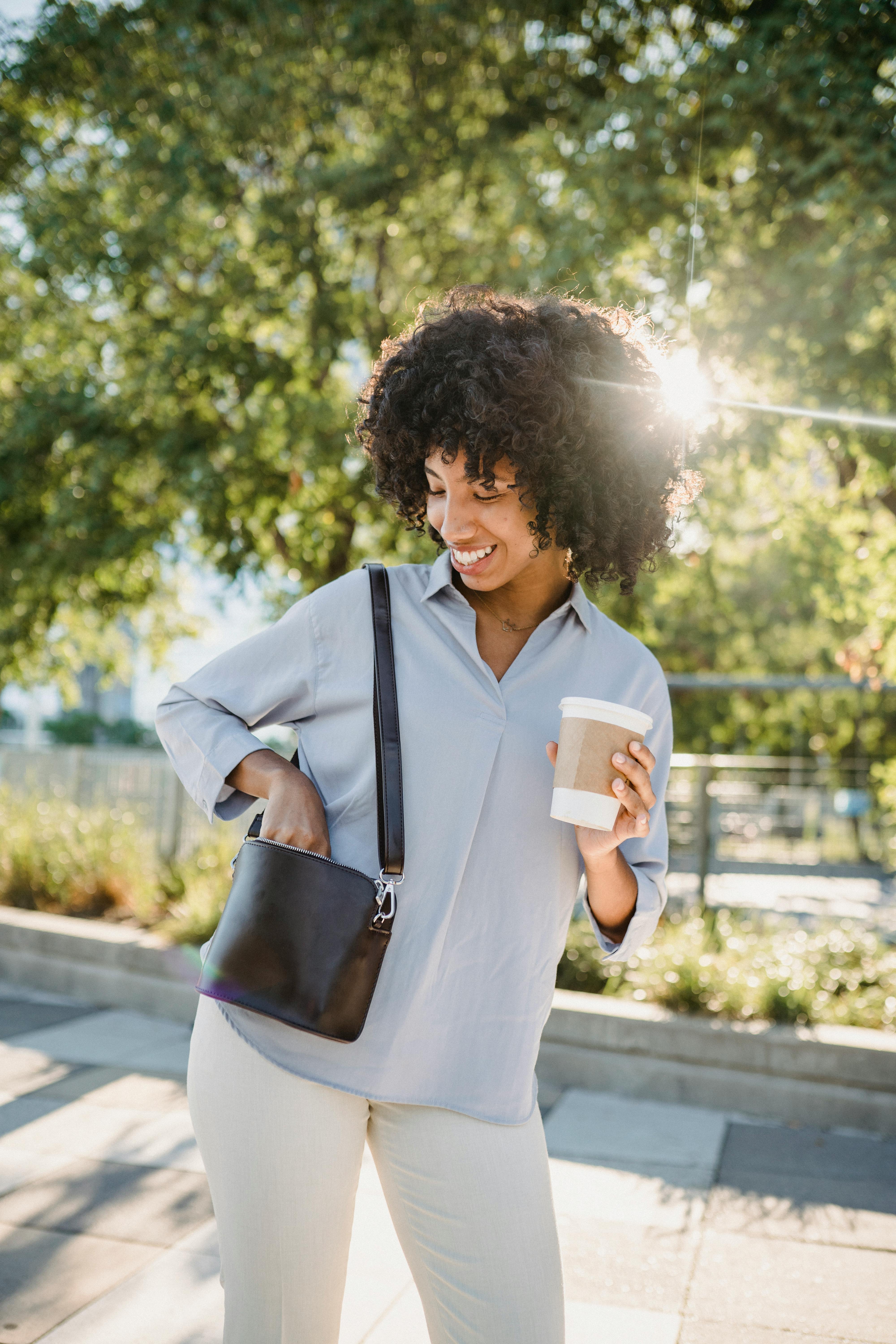 Photo of a Woman Smiling while Holding a Cup of Coffee · Free Stock Photo