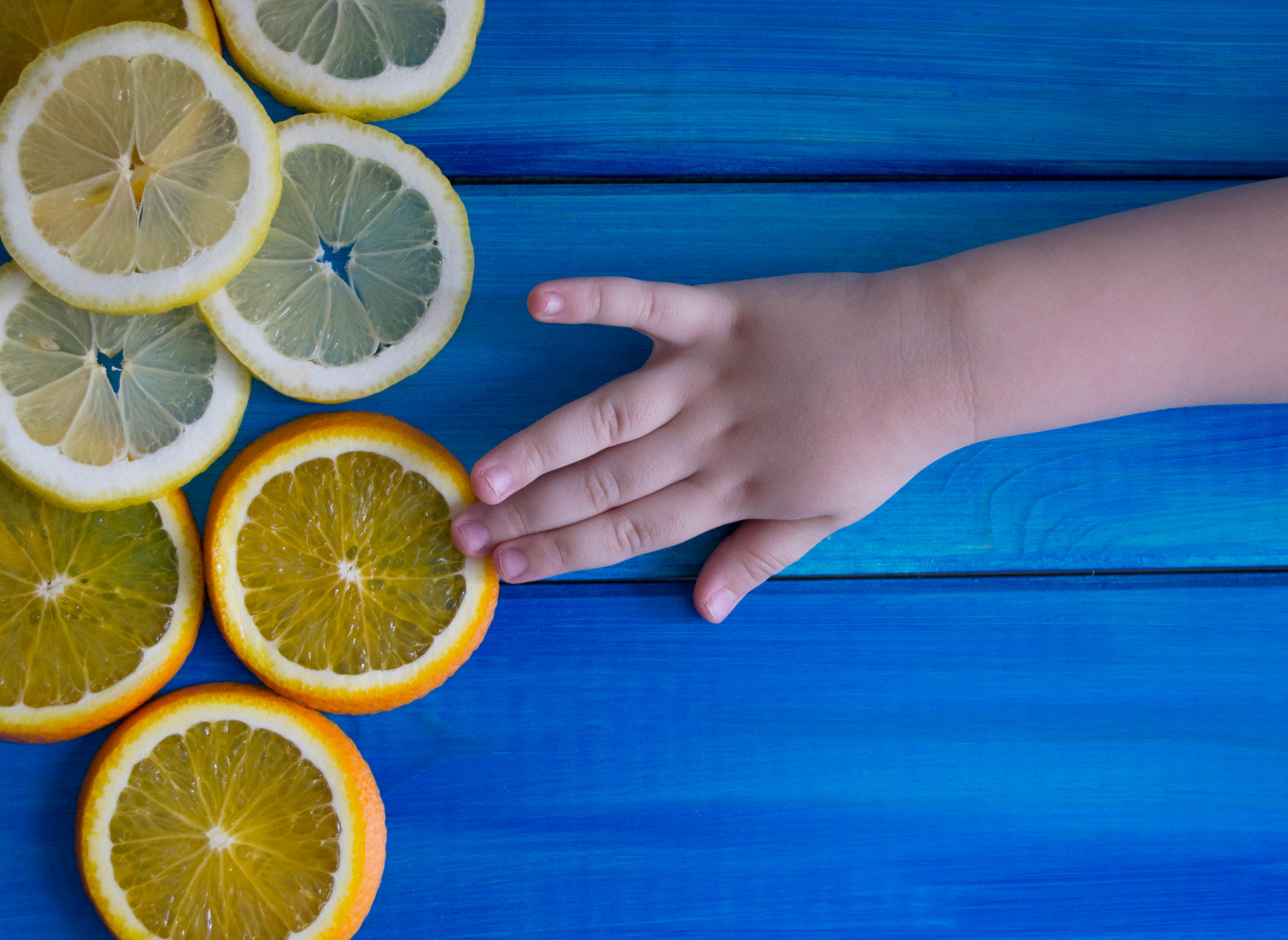 Photo of a Child's Hand Touching a Slice of Orange · Free Stock Photo