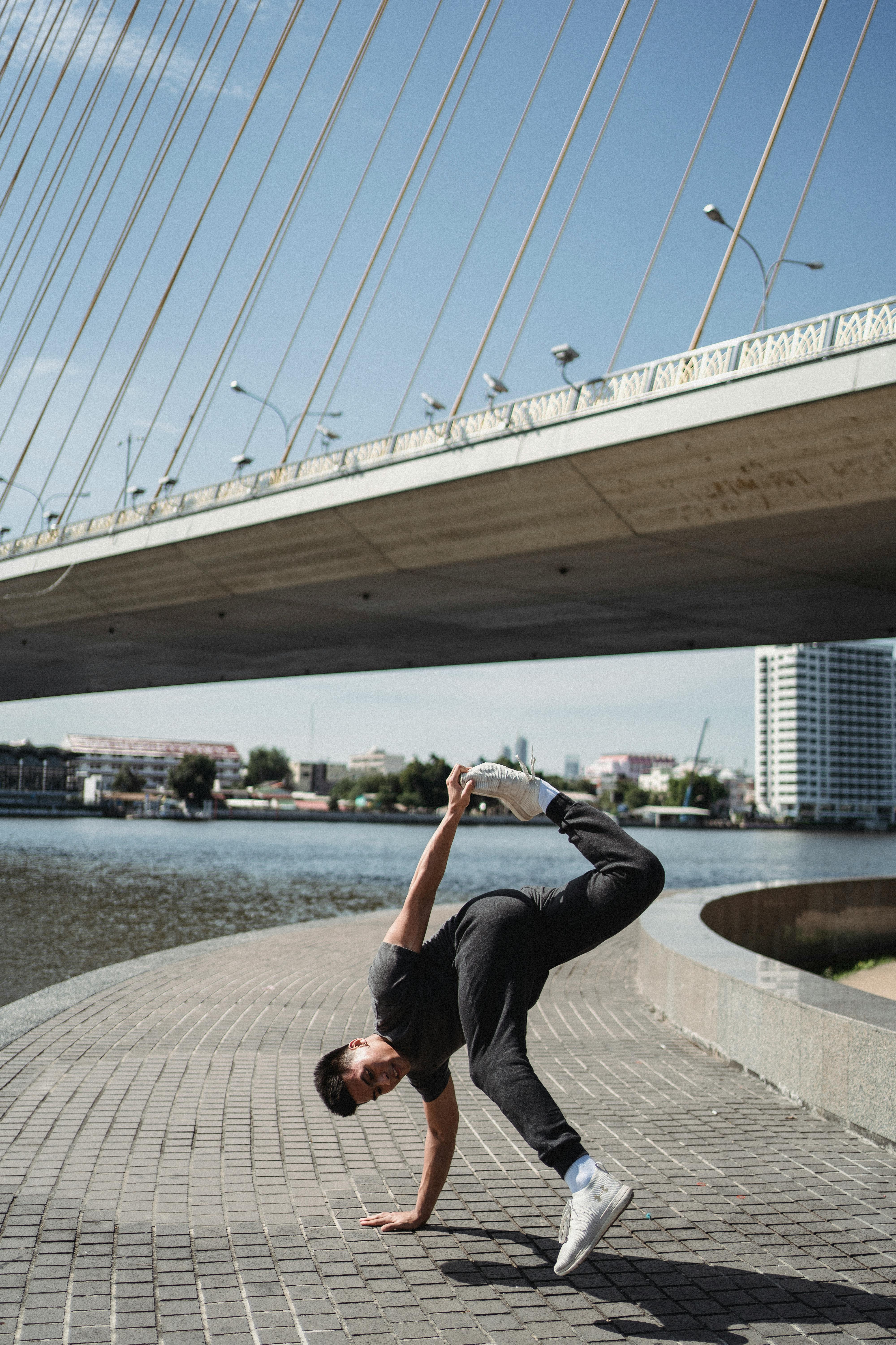 Fit dancer performing trick on city embankment · Free Stock Photo