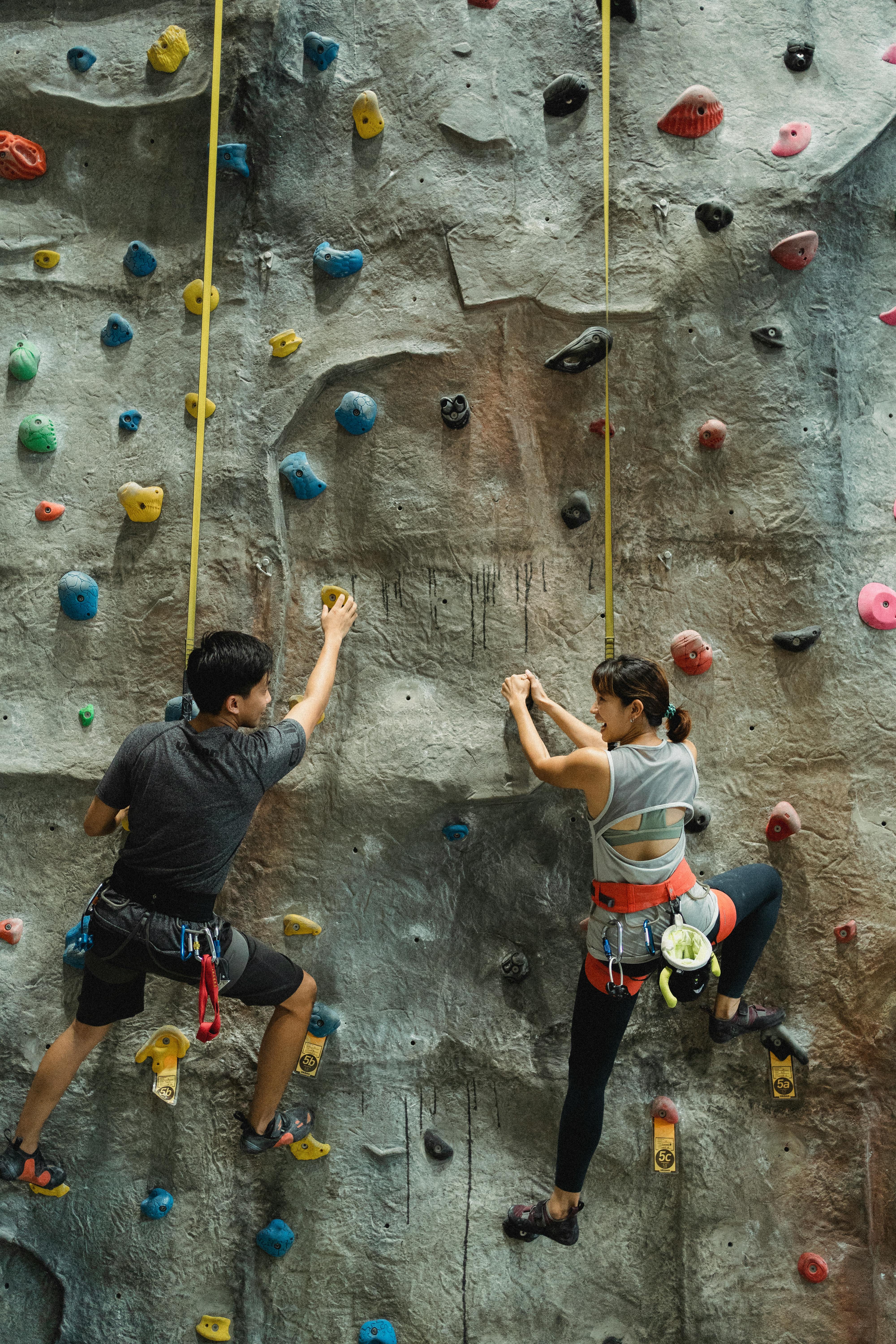 Agile sporty couple hanging on rope and climbing rocky wall · Free ...